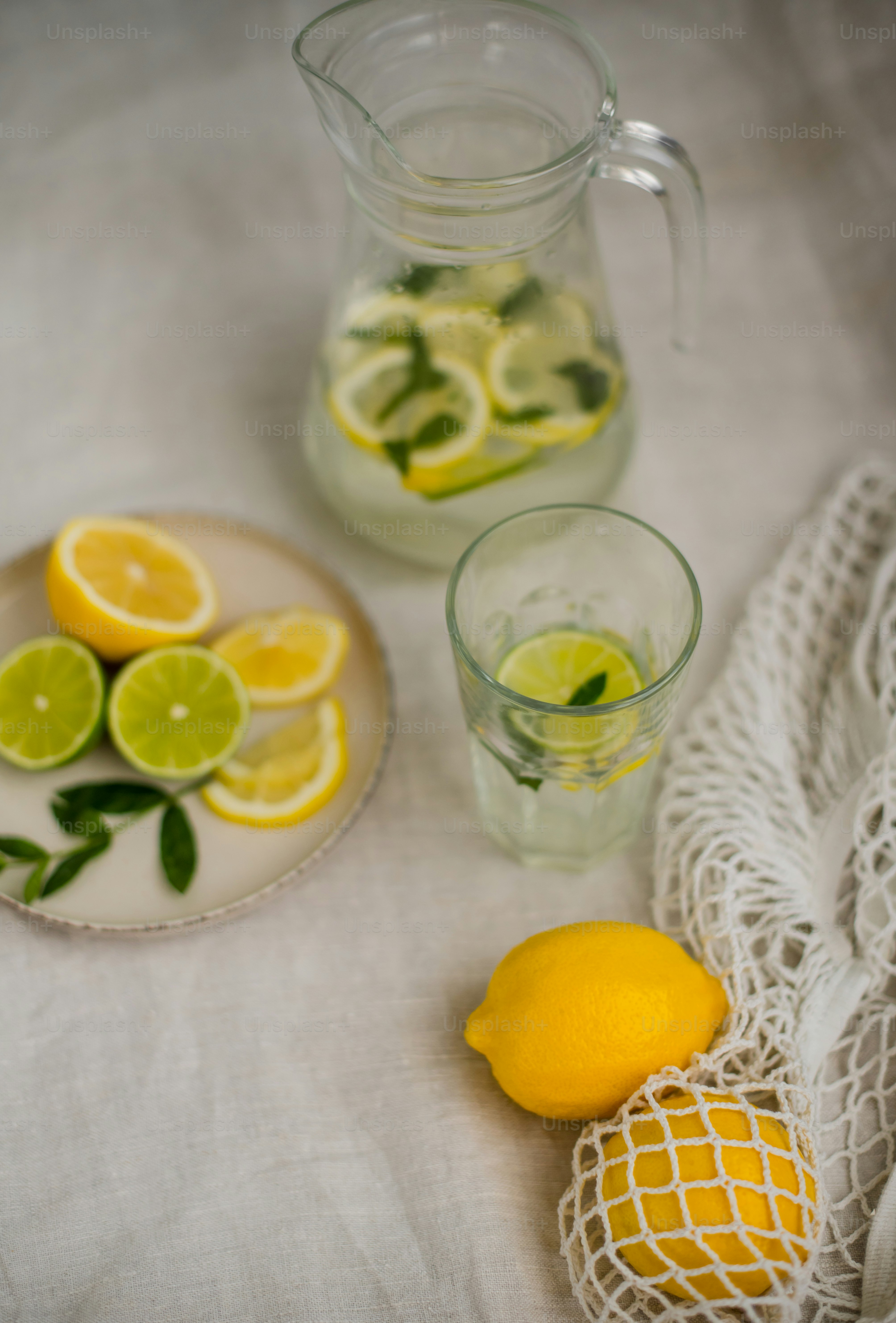 A plate of lemons and limes next to a pitcher of water photo – Fruit ...