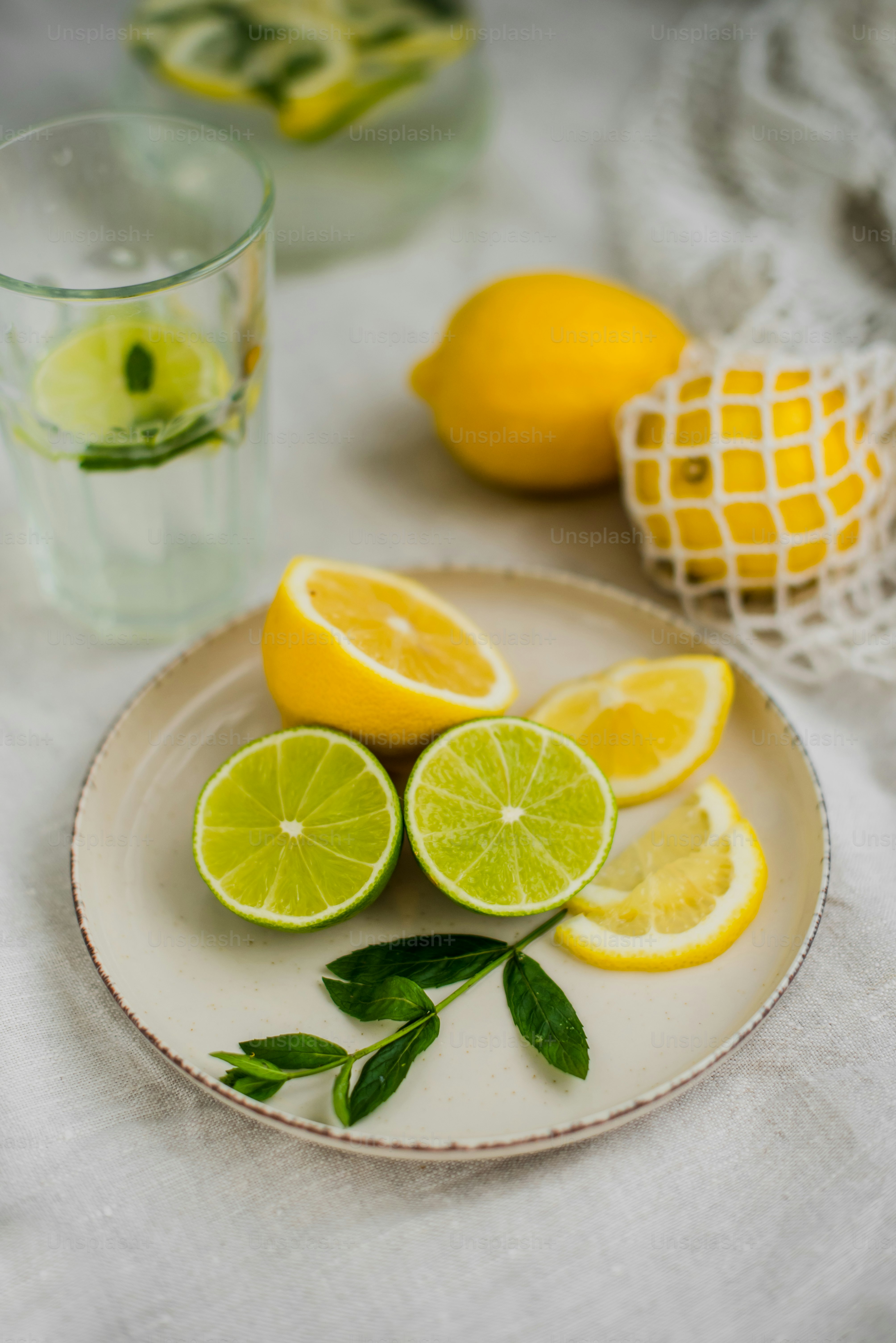 A plate of lemons and limes next to a pitcher of water photo – Citrus ...