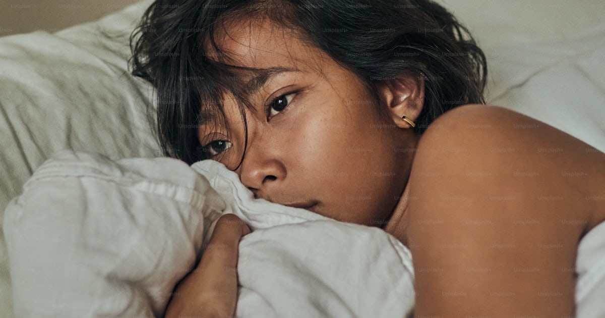 하얀 이불을 들고 침대에 누워 있는 여자 사진 Unsplash의 슬픈 이미지
