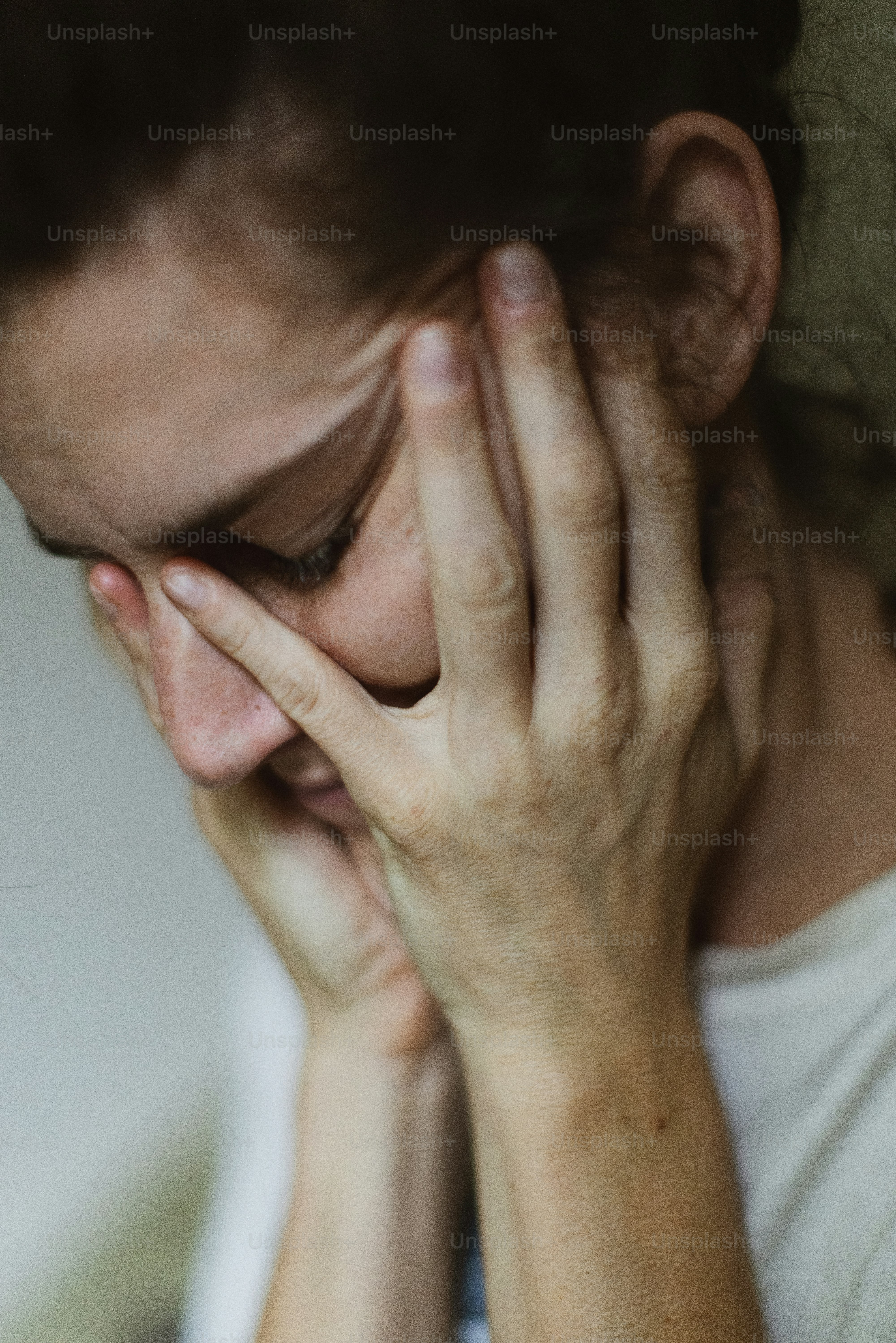 A woman holding her hand to her face photo – Head in hands Image on ...