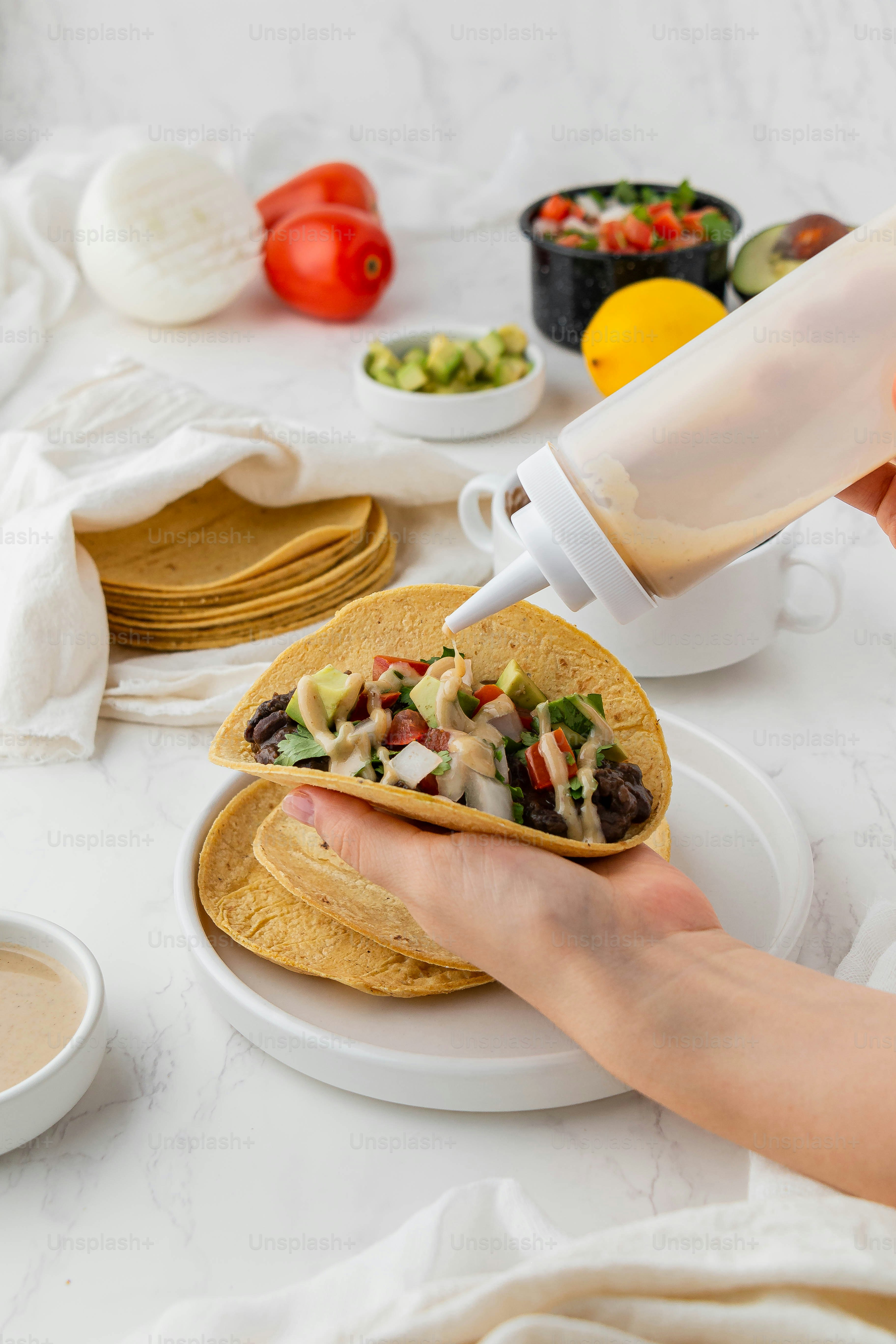 A person is making a taco on a plate photo – Vegan food Image on Unsplash