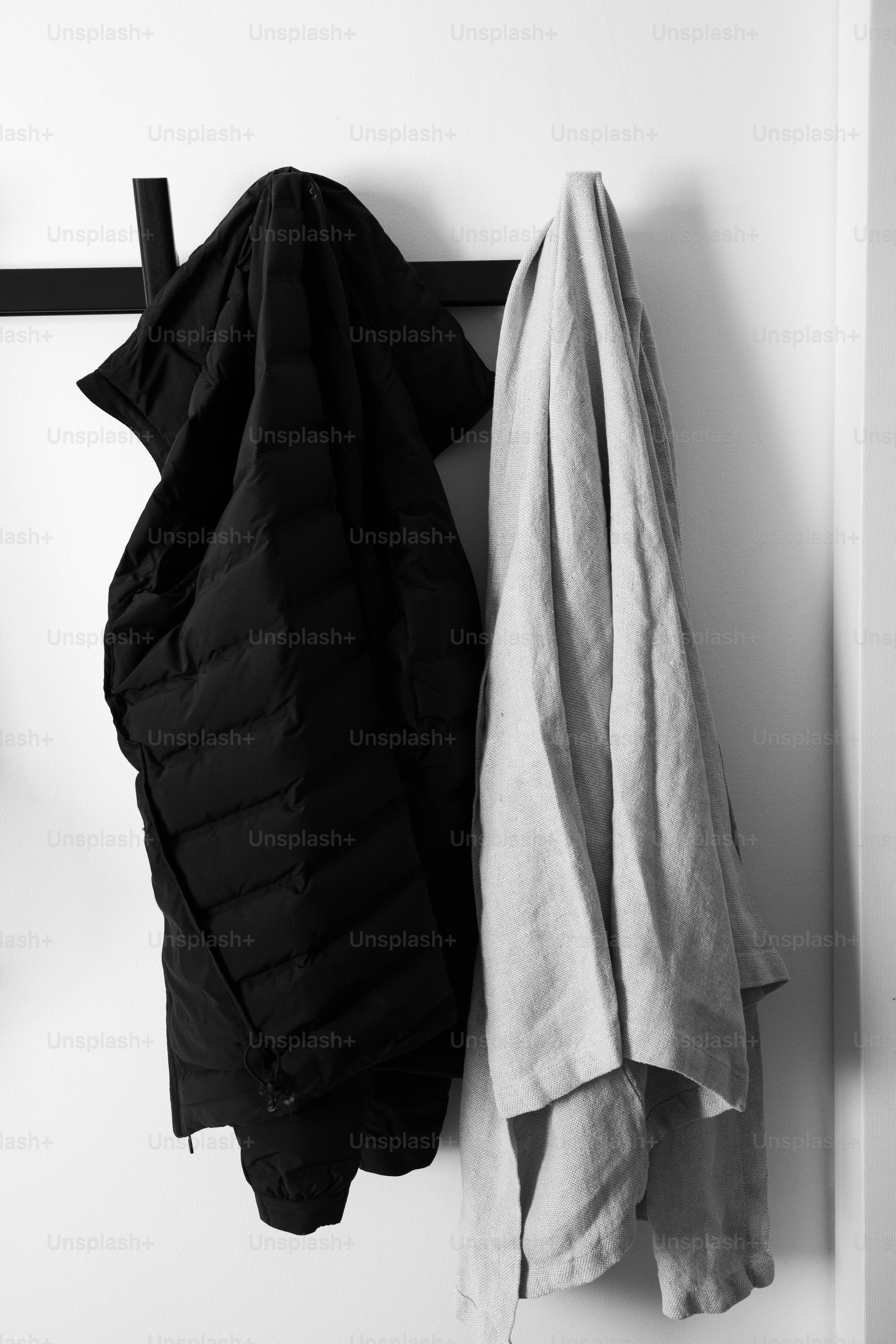 A coat rack with two coats hanging on it photo – Down jacket Image on ...