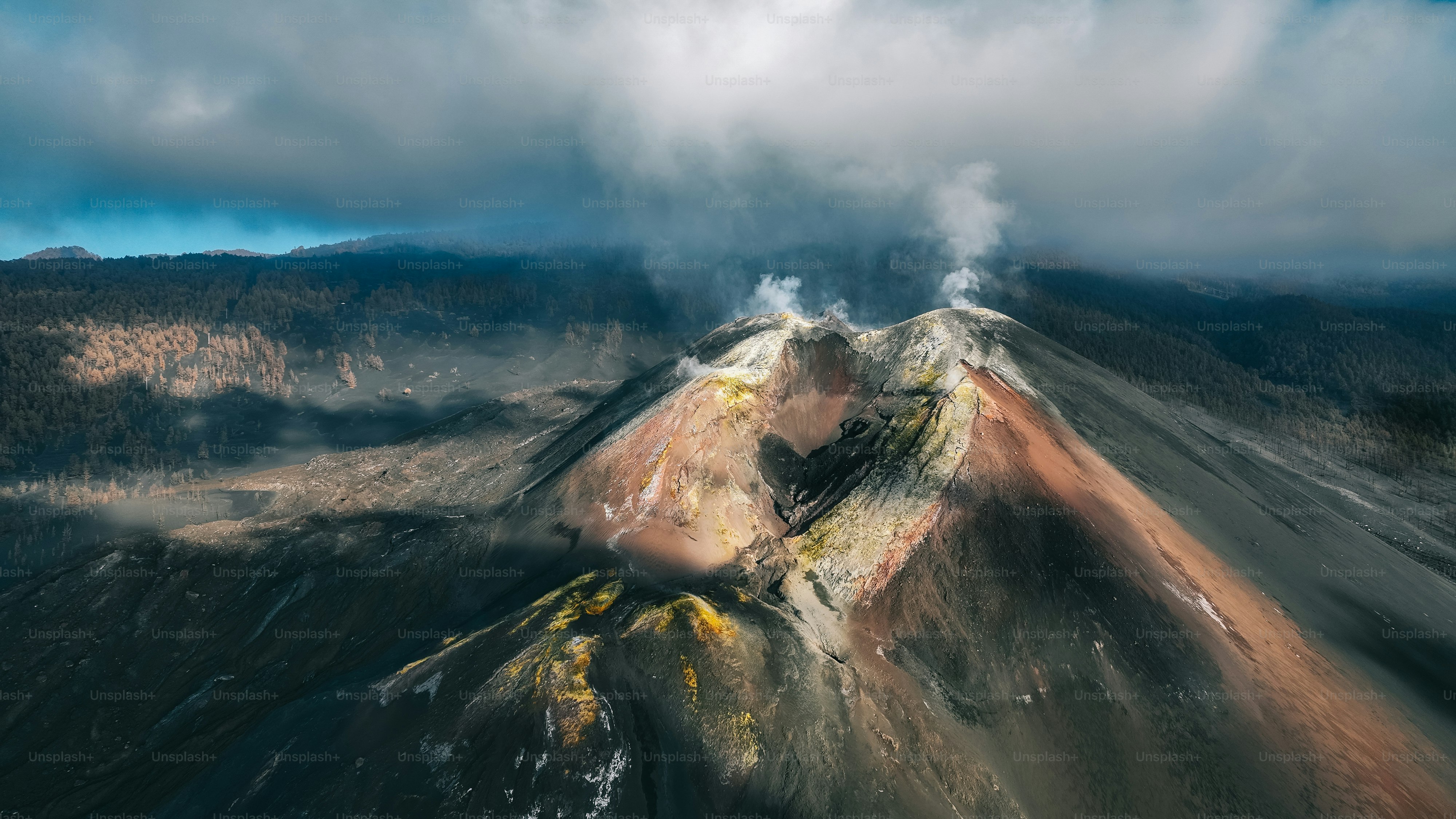 An aerial view of a volcano with steam coming out of it photo ...