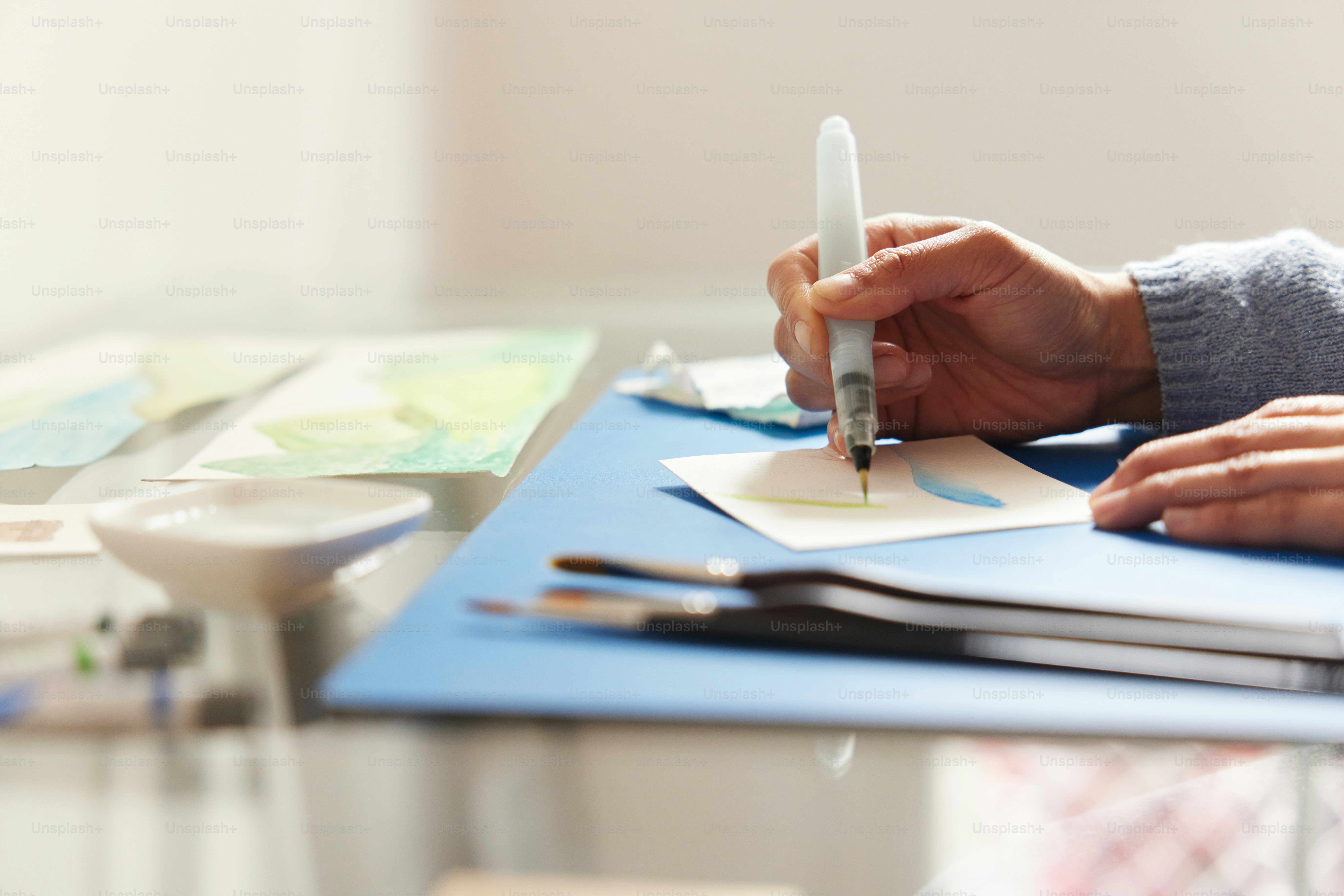 A person writing on a piece of paper with a pen photo – Watercolour ...
