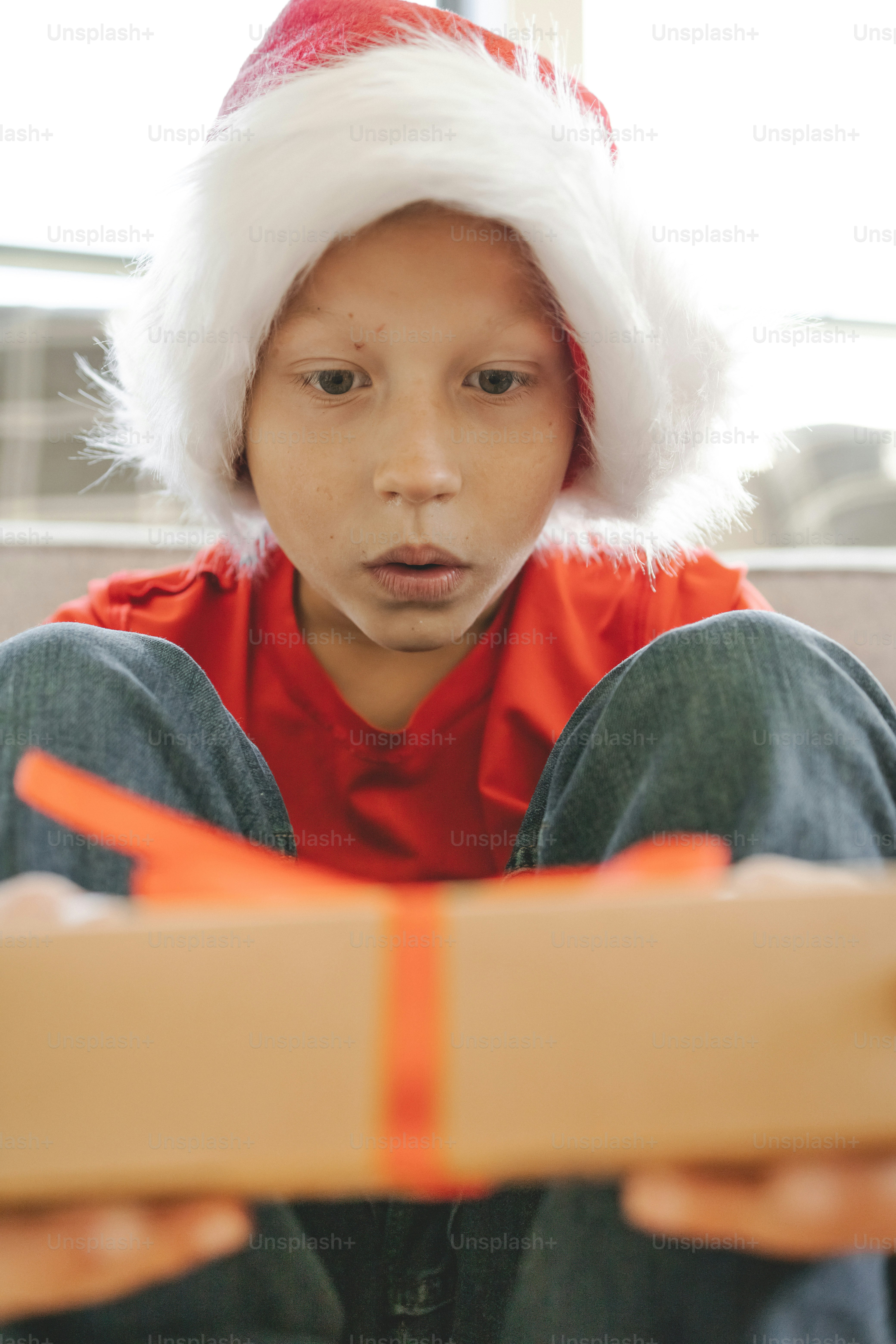 A young boy wearing a santa hat and holding a box photo – Child Image ...