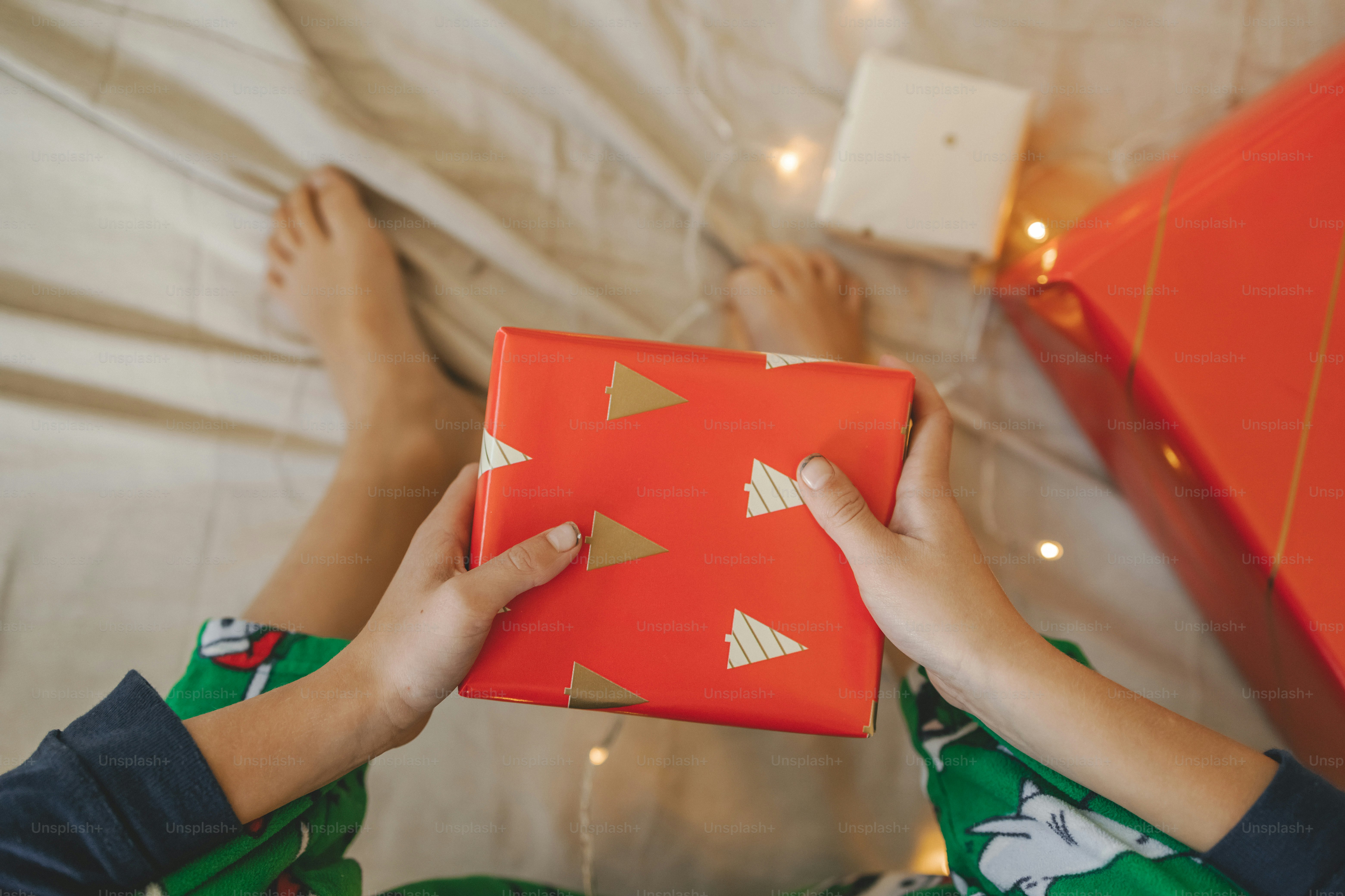 A person holding a red box with gold triangles on it photo – Gift box ...