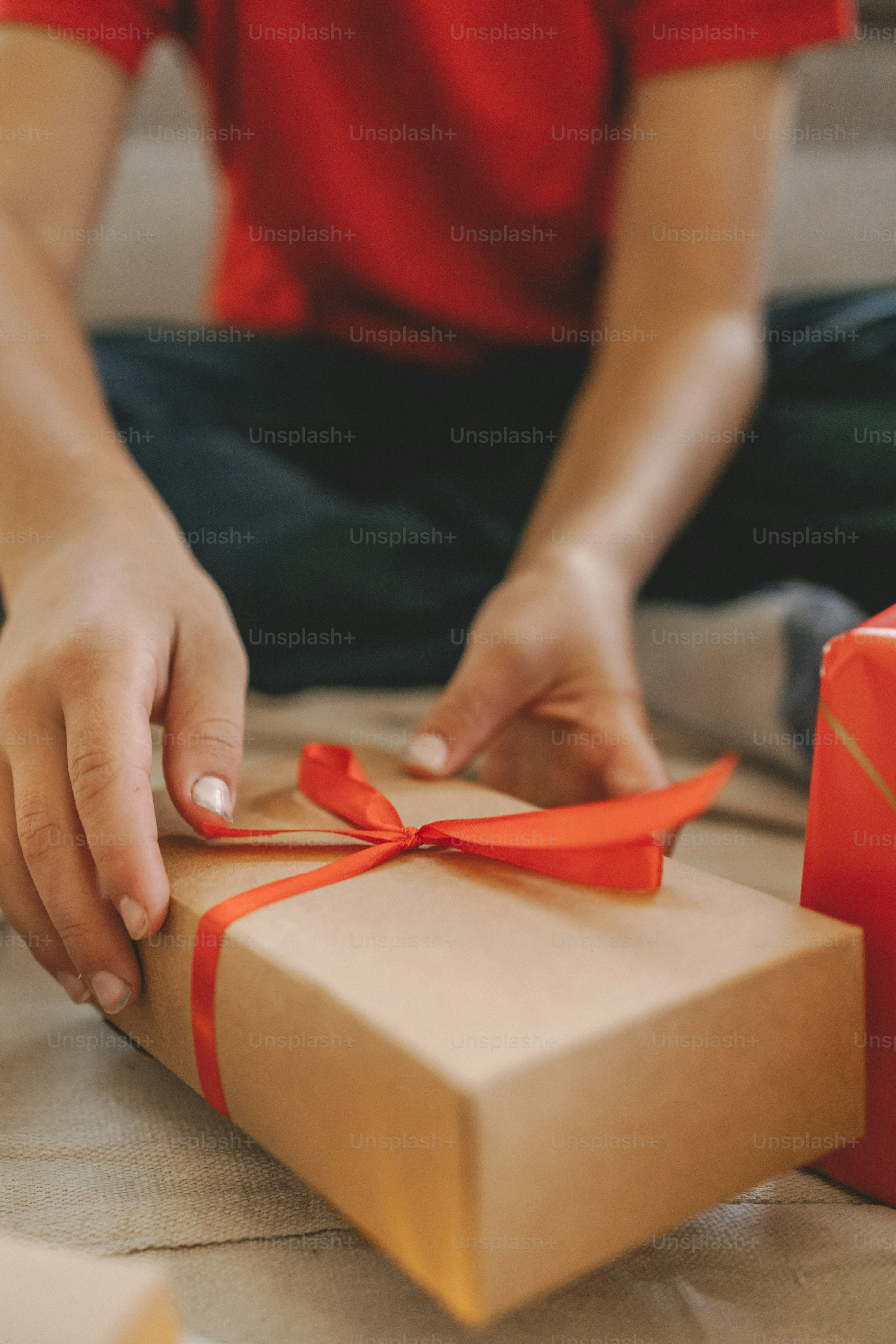A person wrapping a present with a red ribbon photo – Gift Image on ...