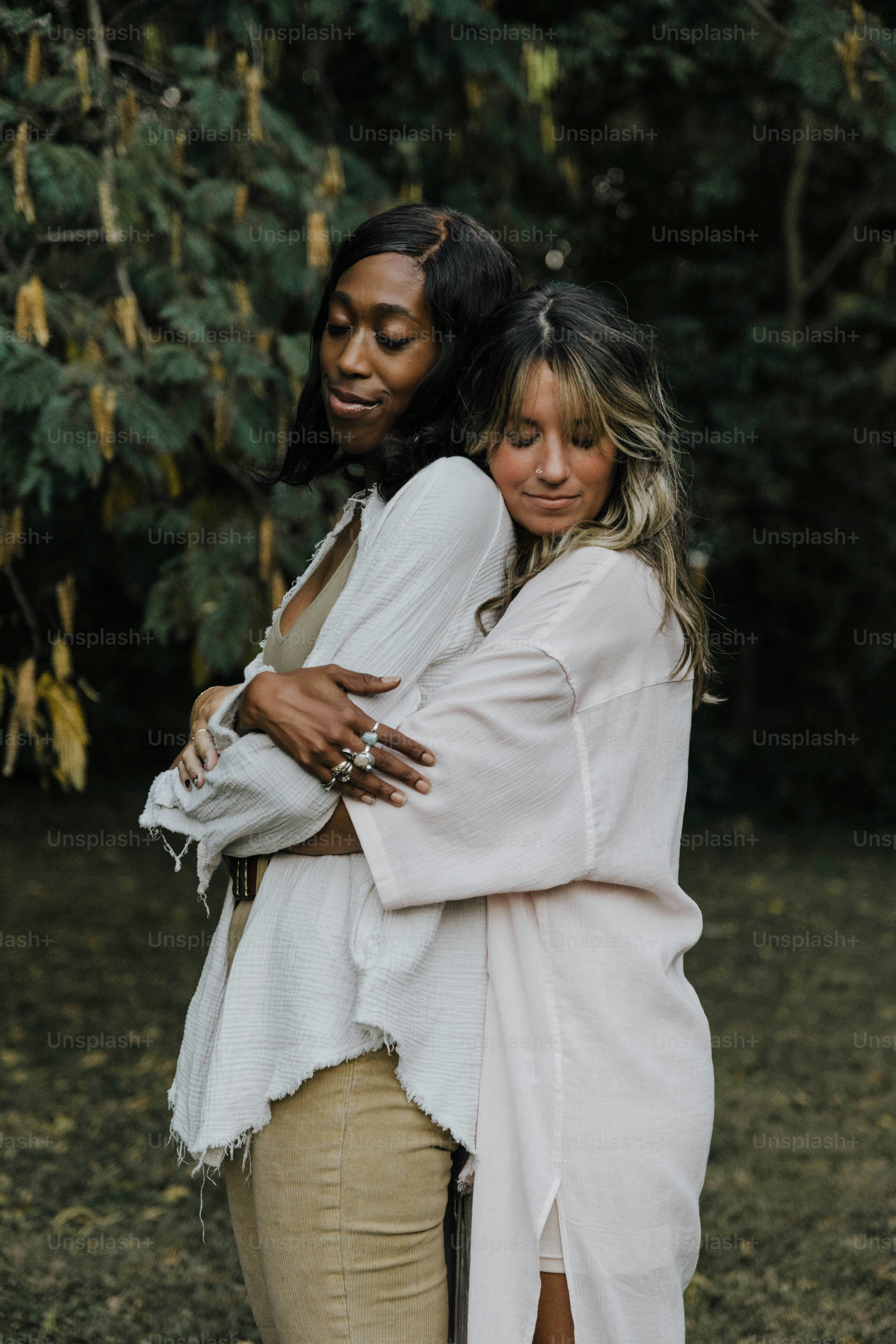 Two women hugging each other in front of trees photo – People Image on ...
