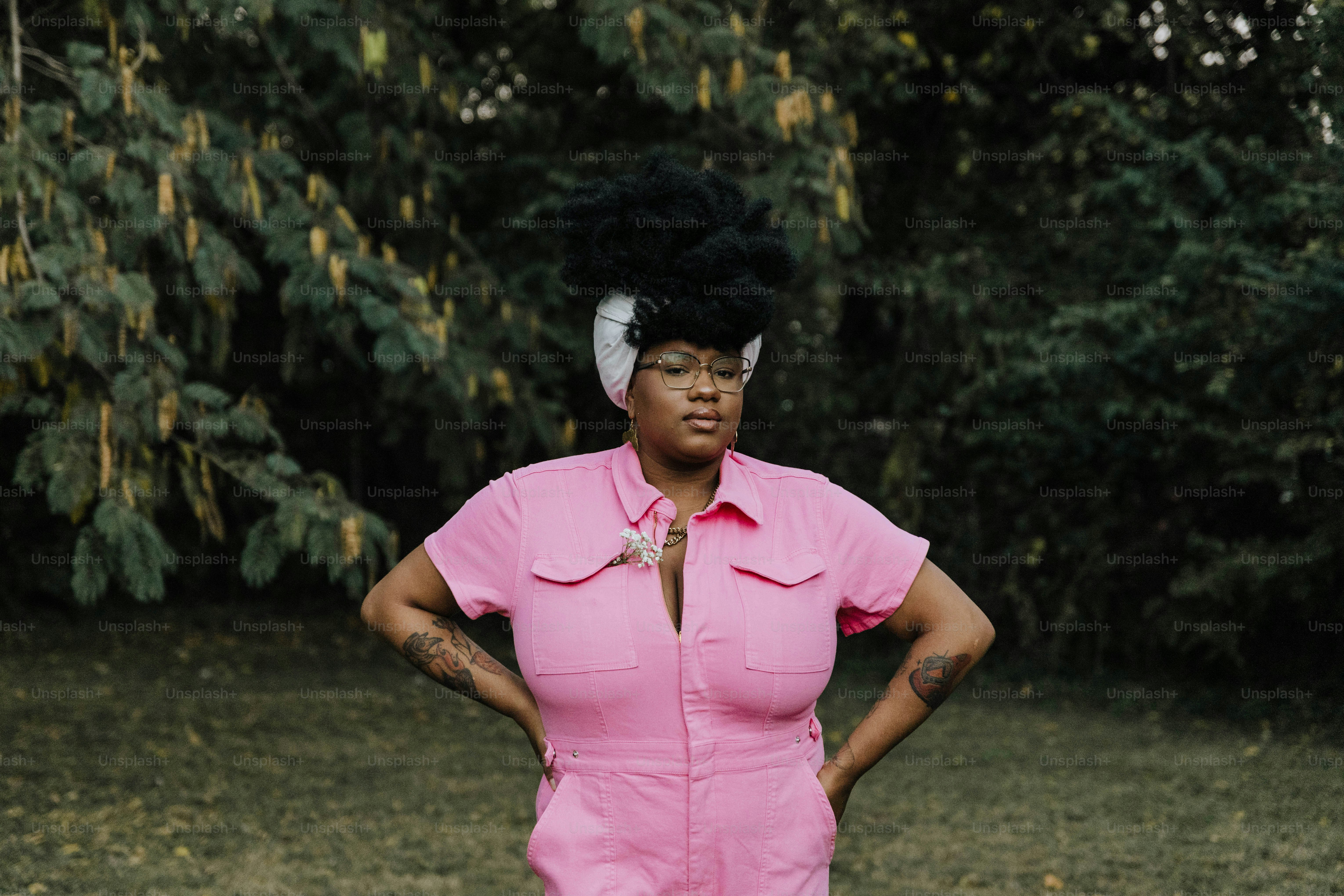 Foto Una mujer con un mono rosa parada en la hierba – Mujer Imagen en ...