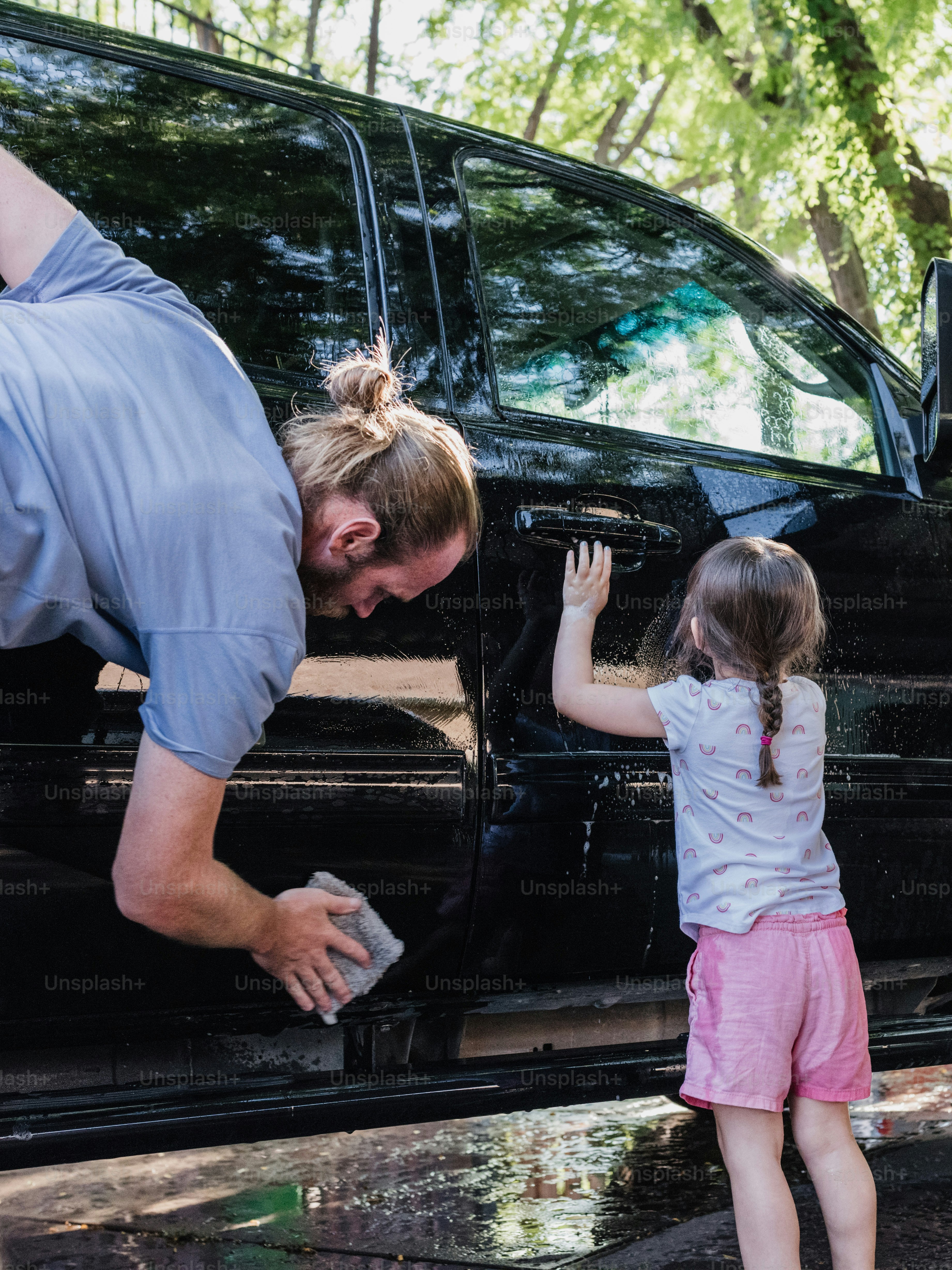 A man helping a little girl get out of a black van photo – Clean car ...
