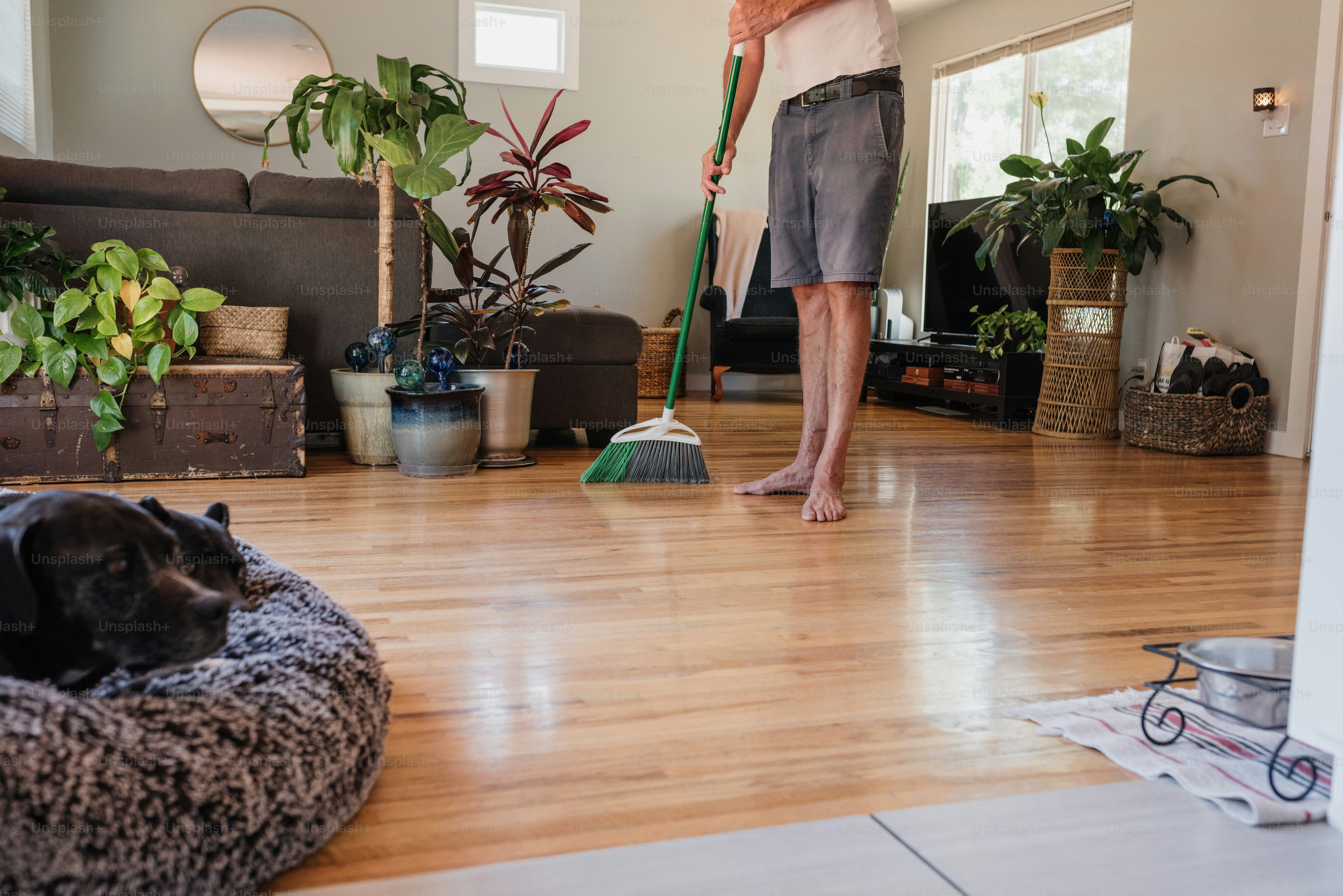 Un hombre con una fregona y un perro en una cama para perros foto ...