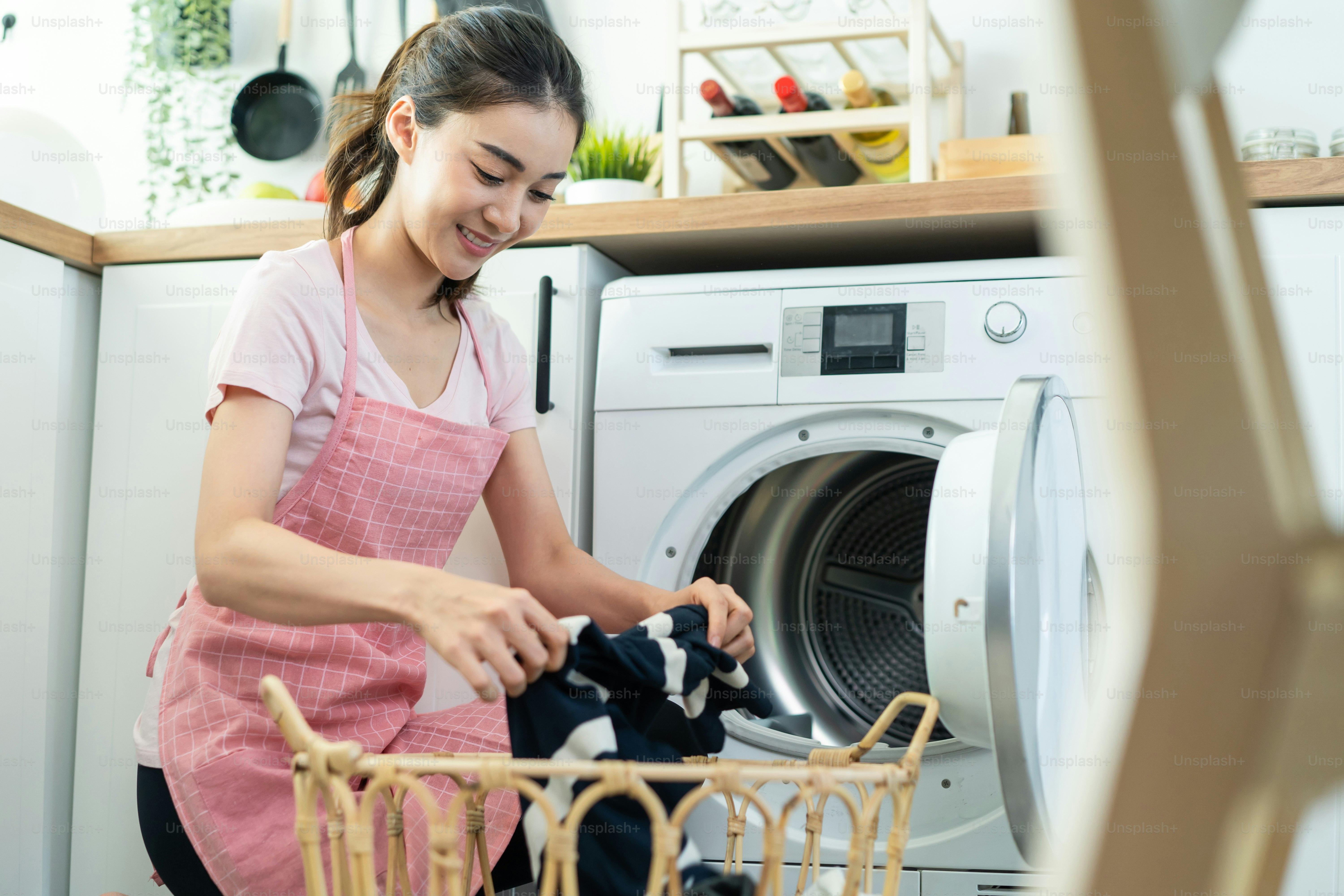 Asian beautiful woman put dirty clothes to washing machine in house ...