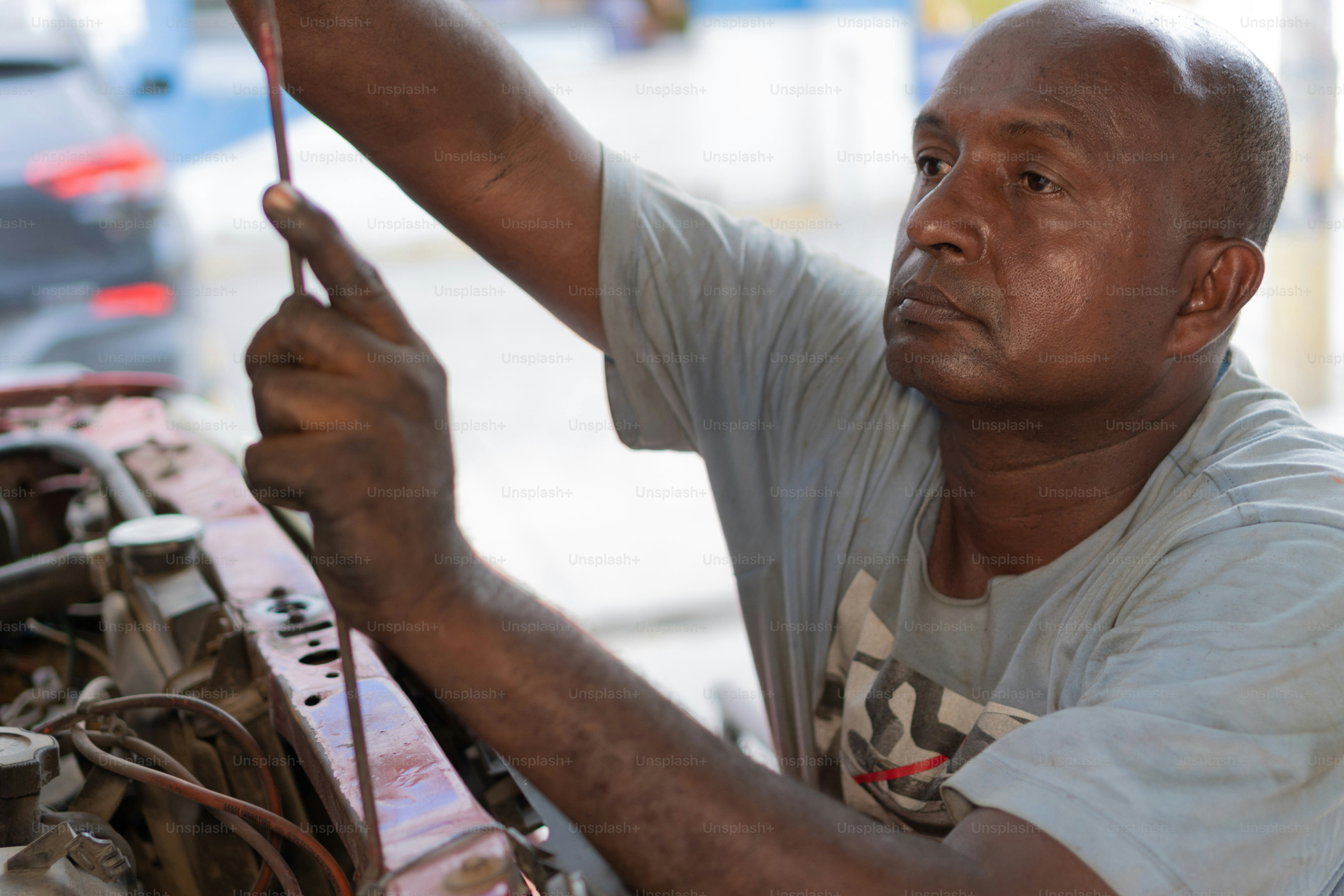Male mechanic working on a vehicle at a car service station. Technician ...