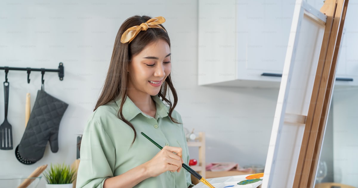 아시아의 젊은 재능 있는 여성 예술가가 집에서 그림 보드에 색칠하고 있다 매력적인 아름다운 여성은 수채화 물감과 브러시로 예술