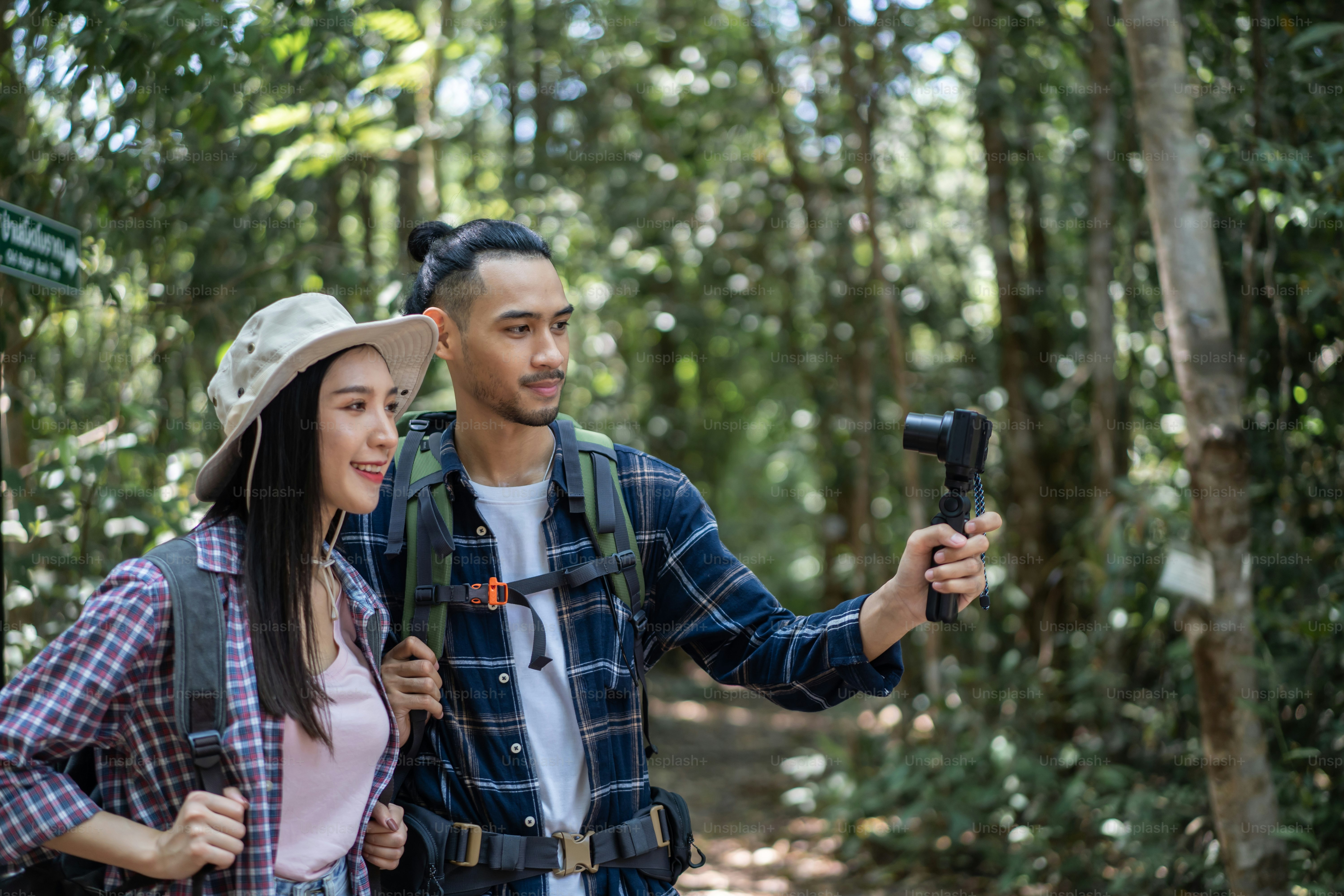 Asian young couple backpacker vlogger traveling in the forest alone ...