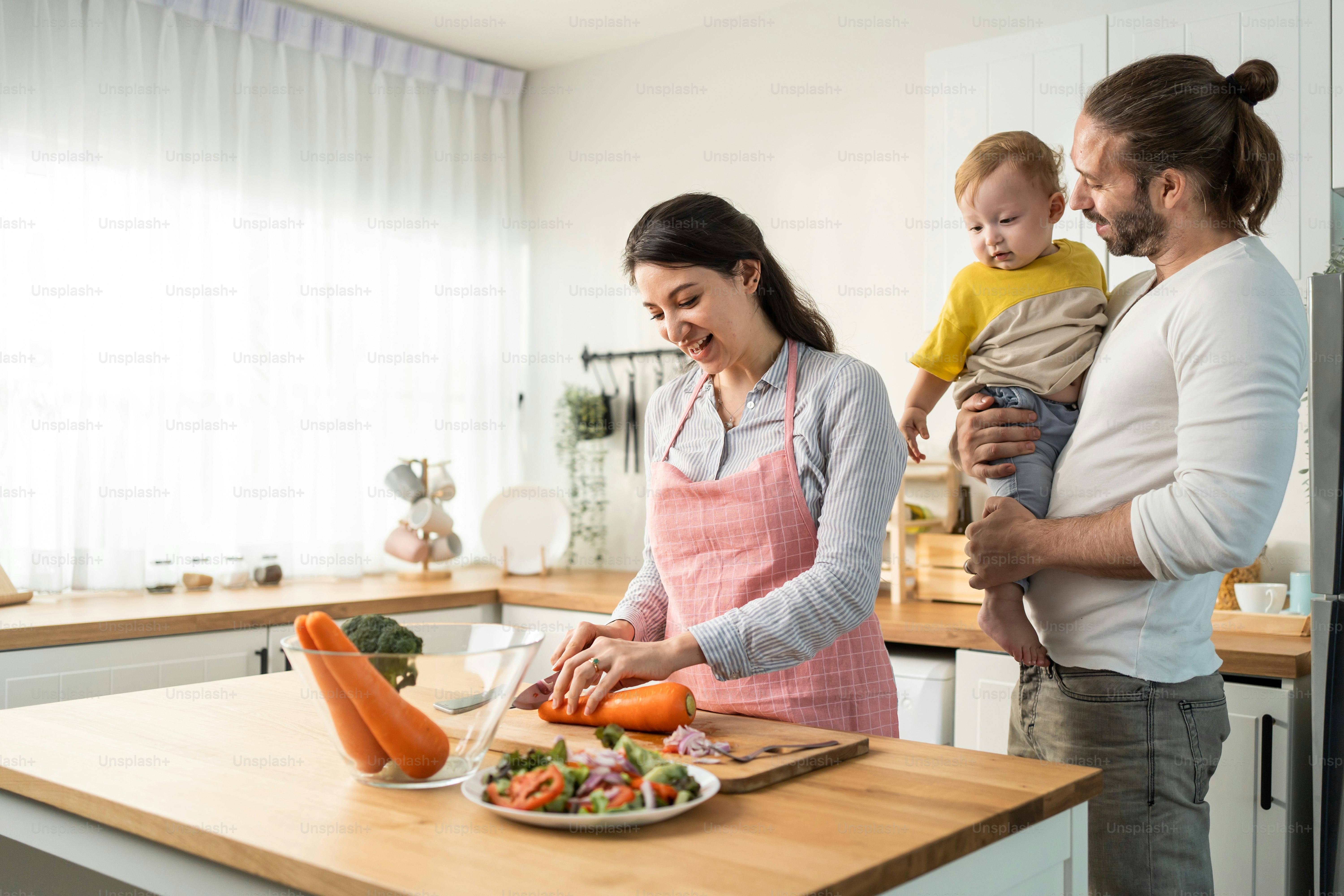 Caucasian beautiful parents cook food with baby boy toddler in kitchen ...