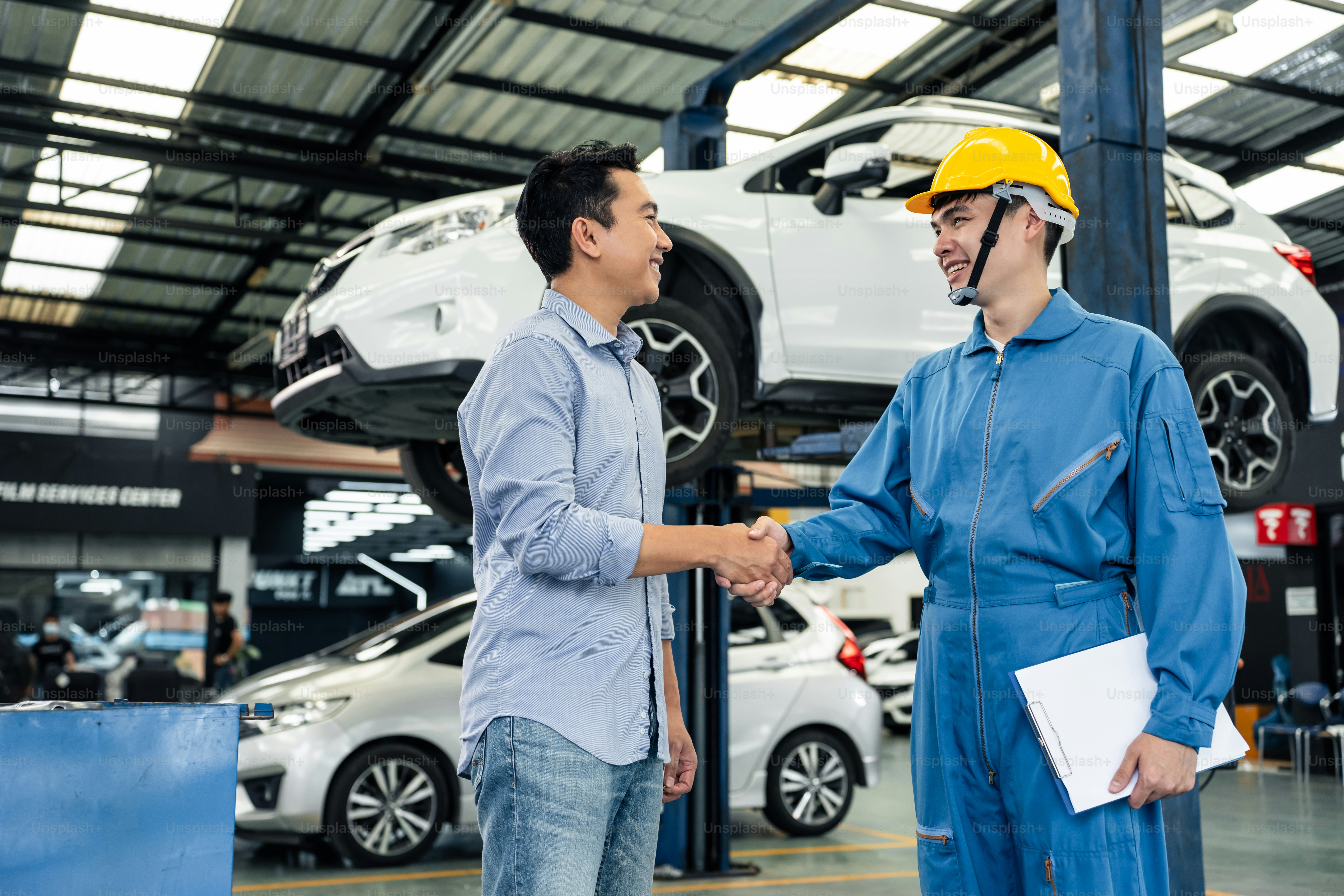 Asian automotive mechanic repairman handshake with client in garage ...