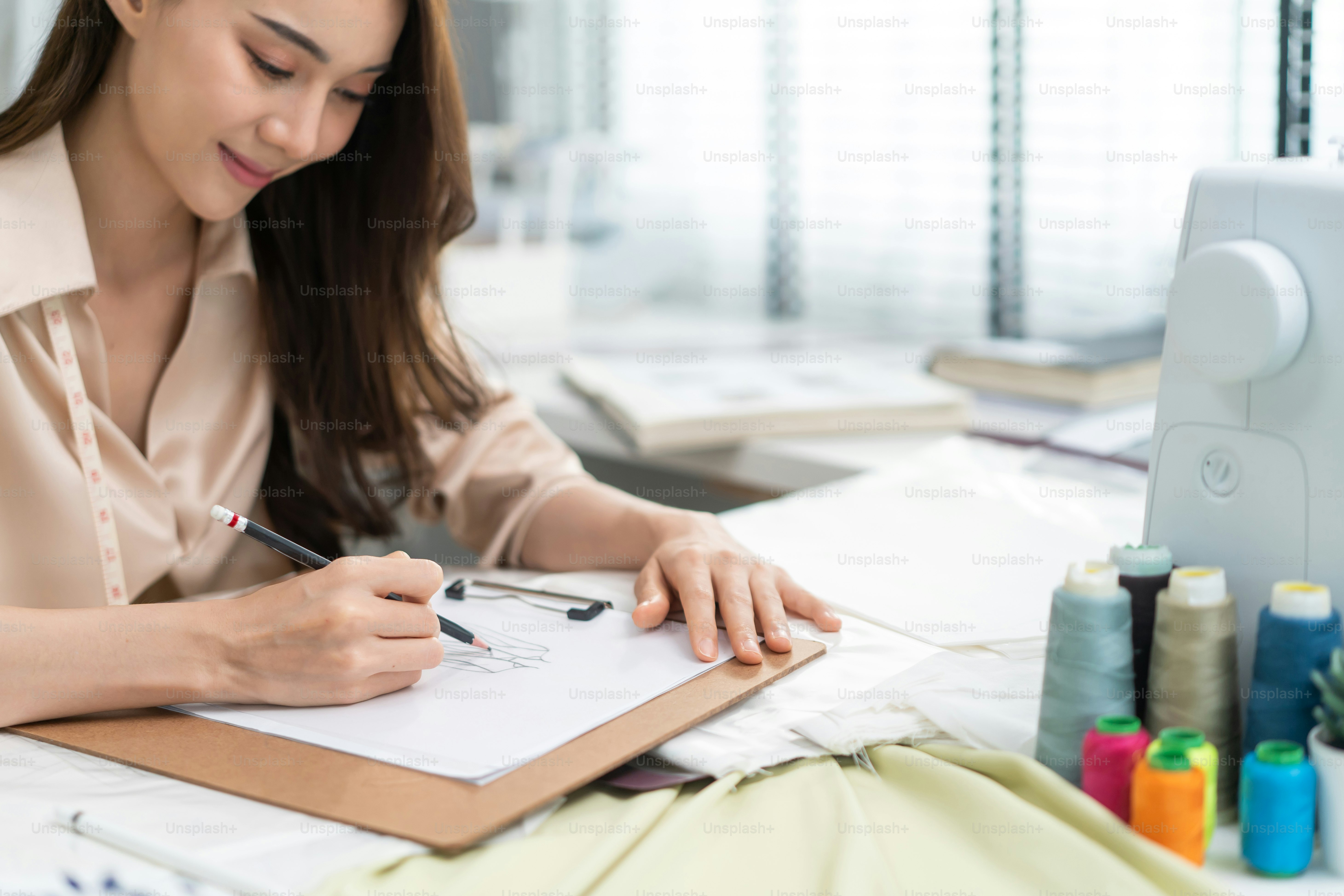 Asian tailor woman working to design new clothes in tailoring atelier ...