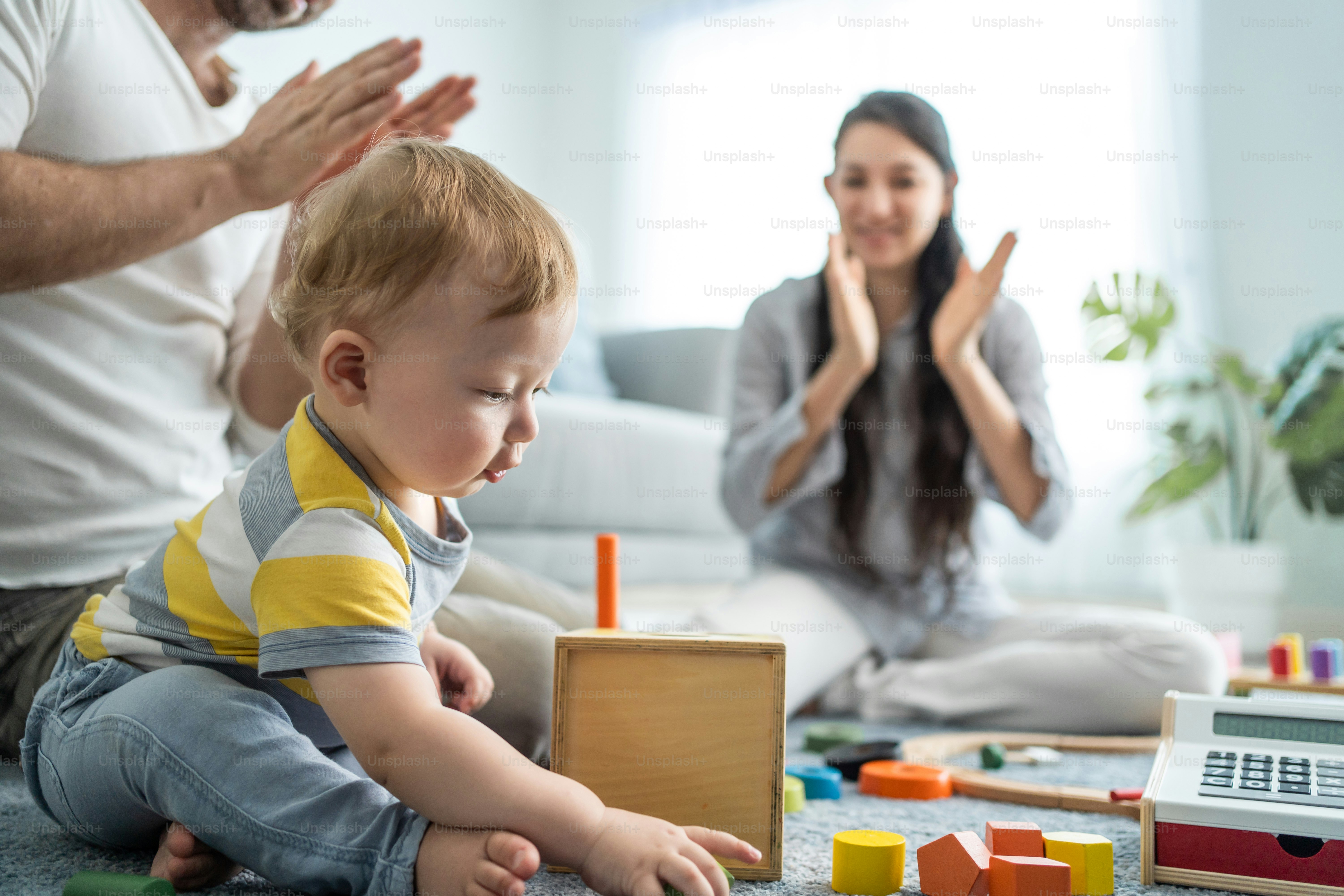 Caucasian loving parent looking at baby toddler playing in living room ...