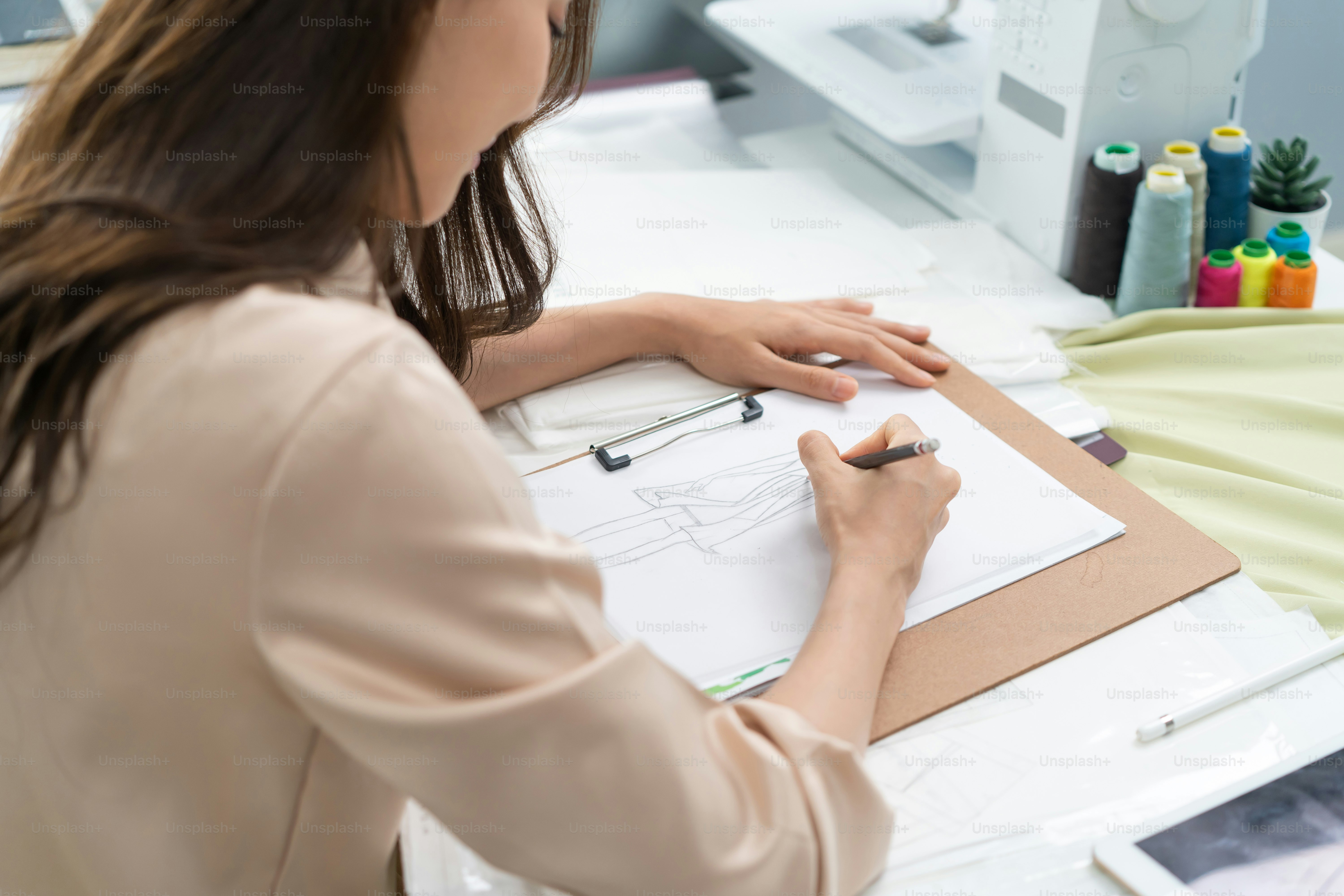 Foto zum Thema Asiatische schöne Schneiderin, die im Schneideratelier ...