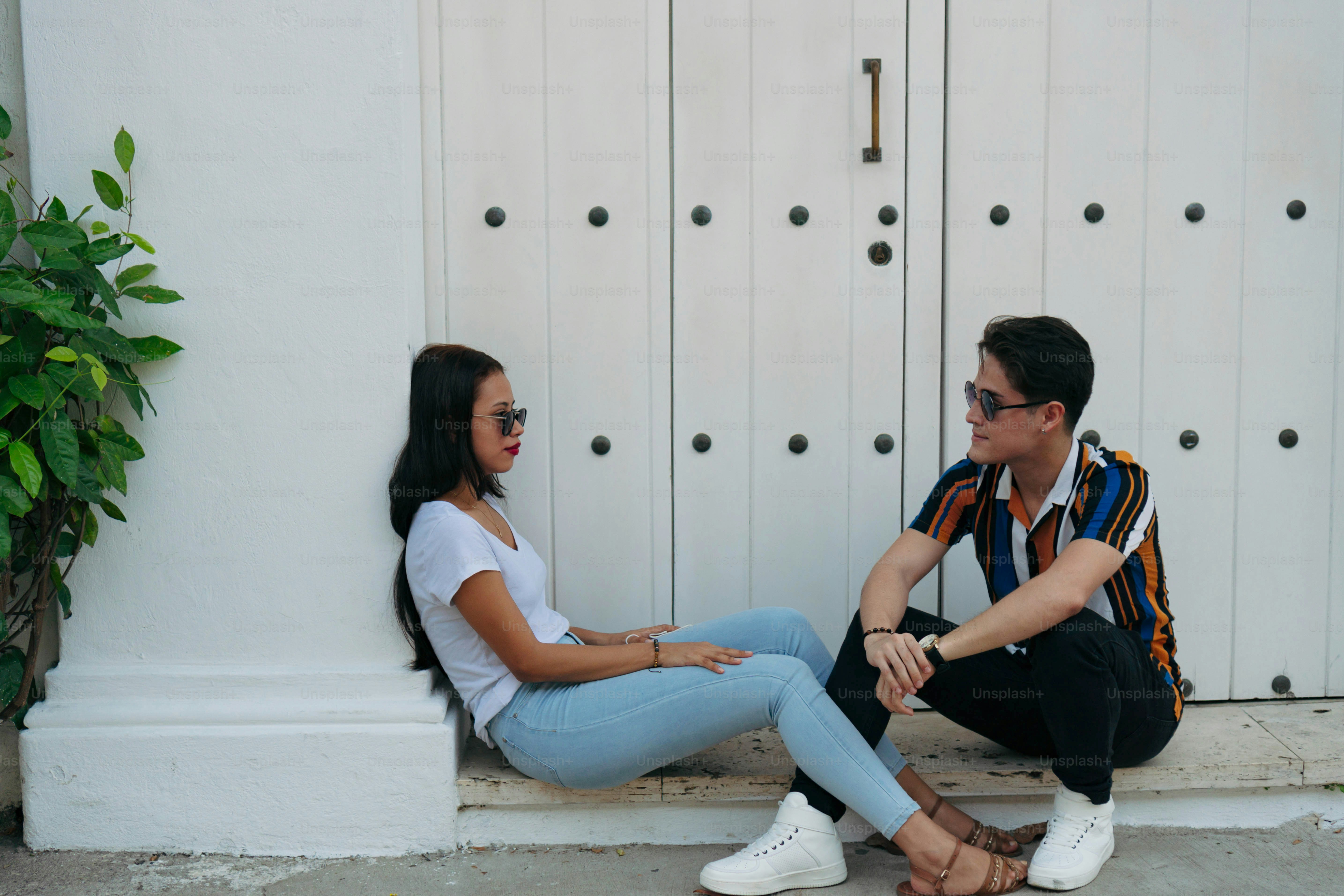 Image of a young man and woman dressed informally talking while sitting ...