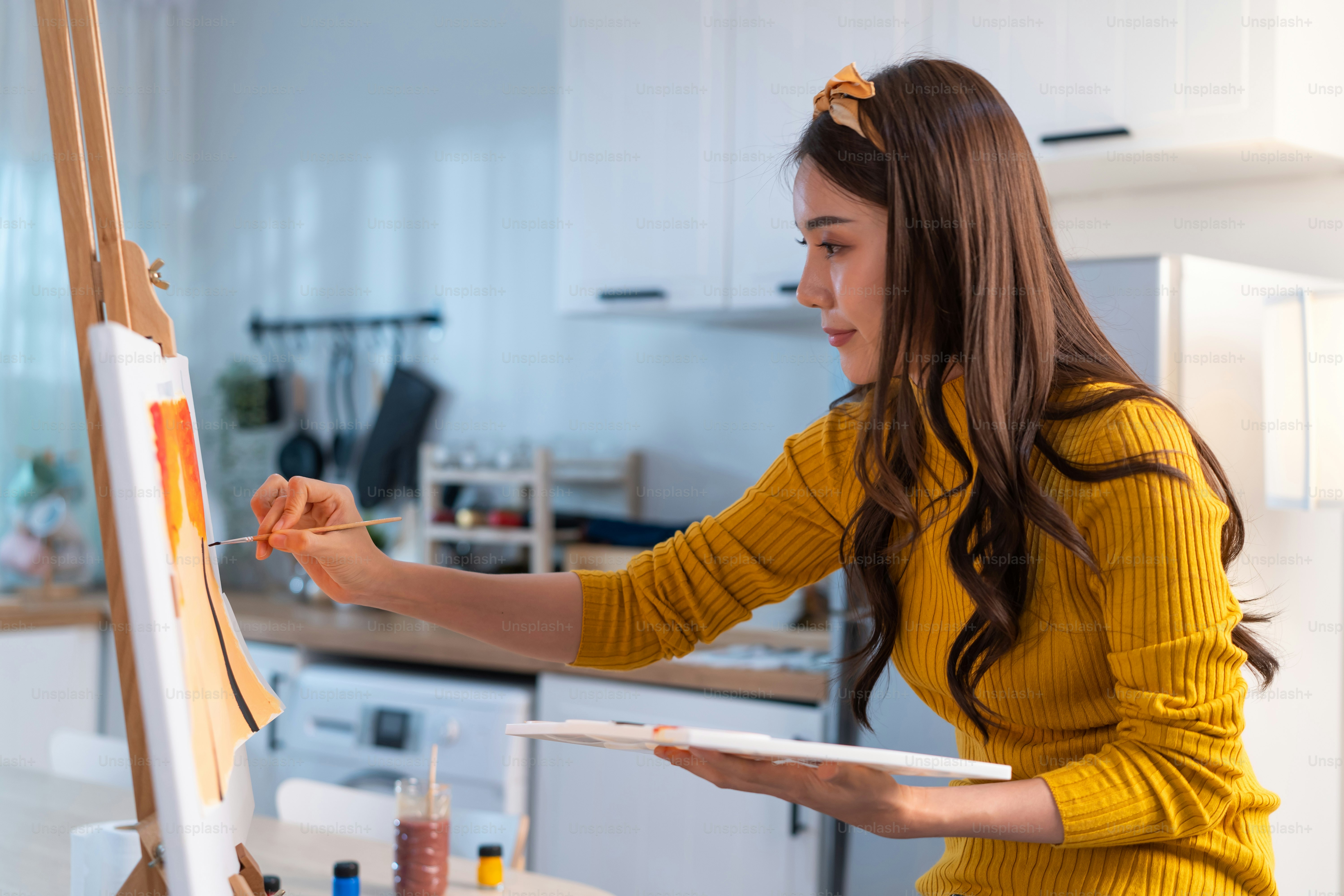 Asian young talented woman artist coloring on painting board in house ...
