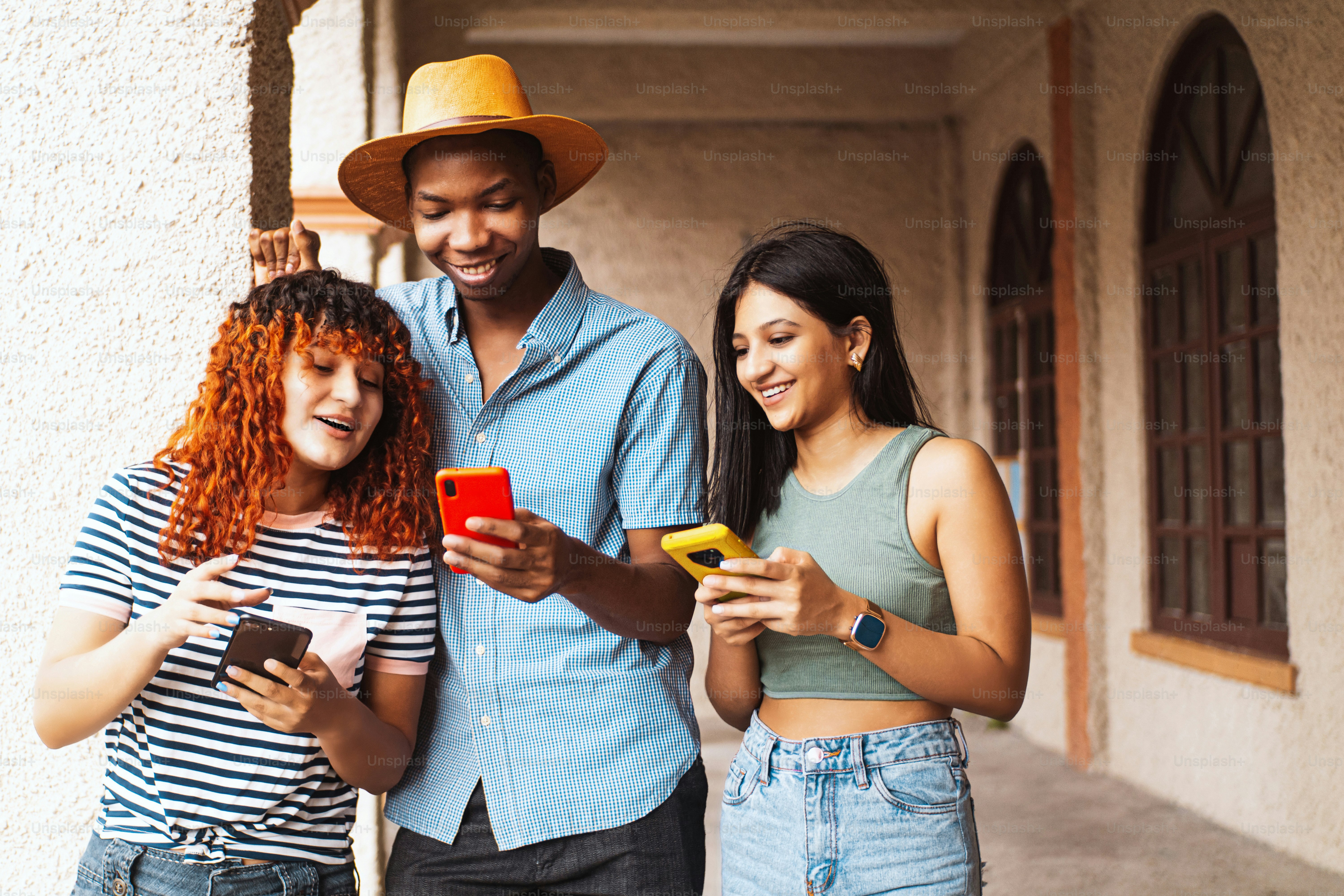 Young friends using a phones looking social media outdoor. photo – Hat ...