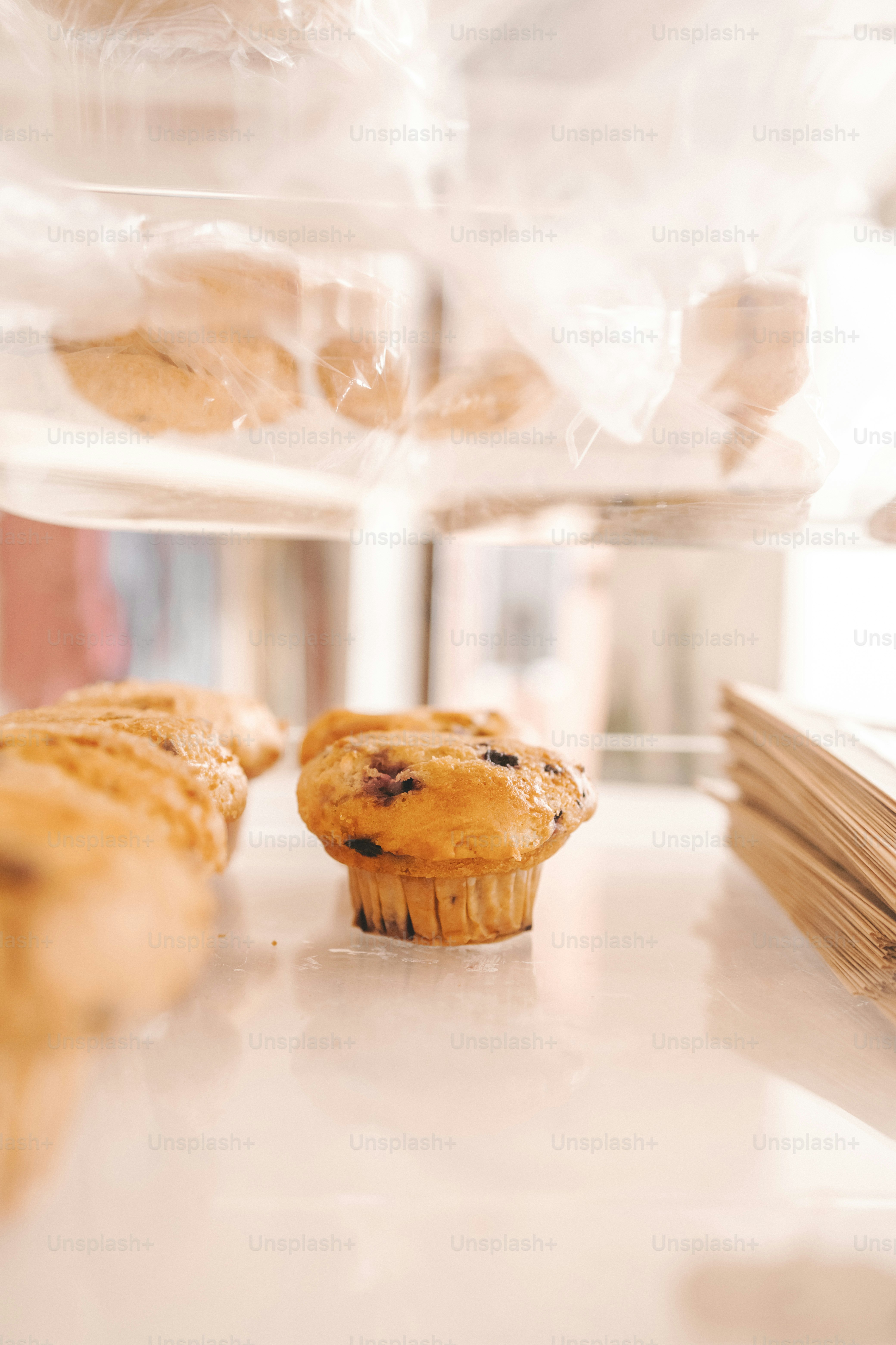 Two muffins sitting on a counter in a bakery photo – Muffin Image on ...