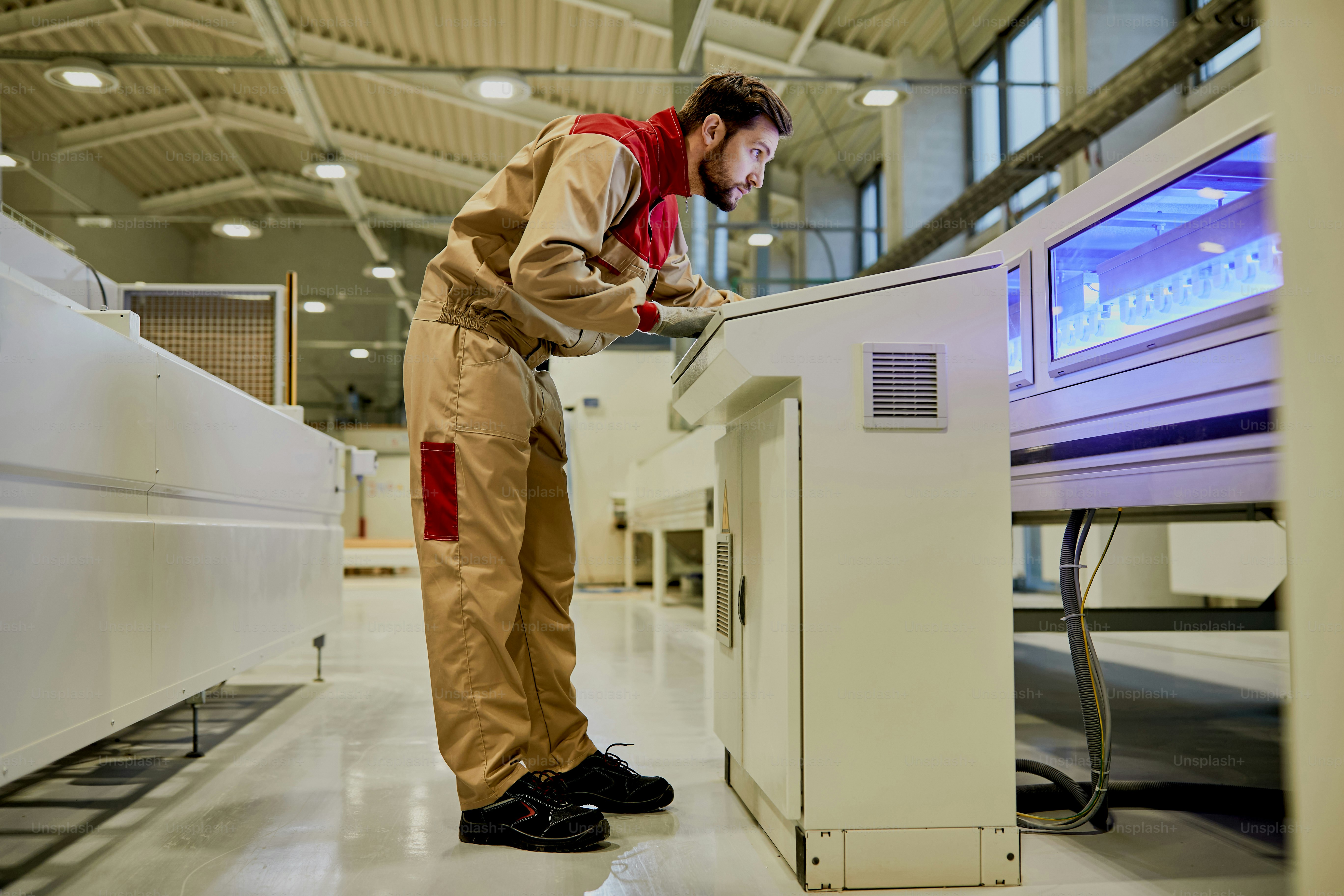 Full length of factory worker working on automated production line ...