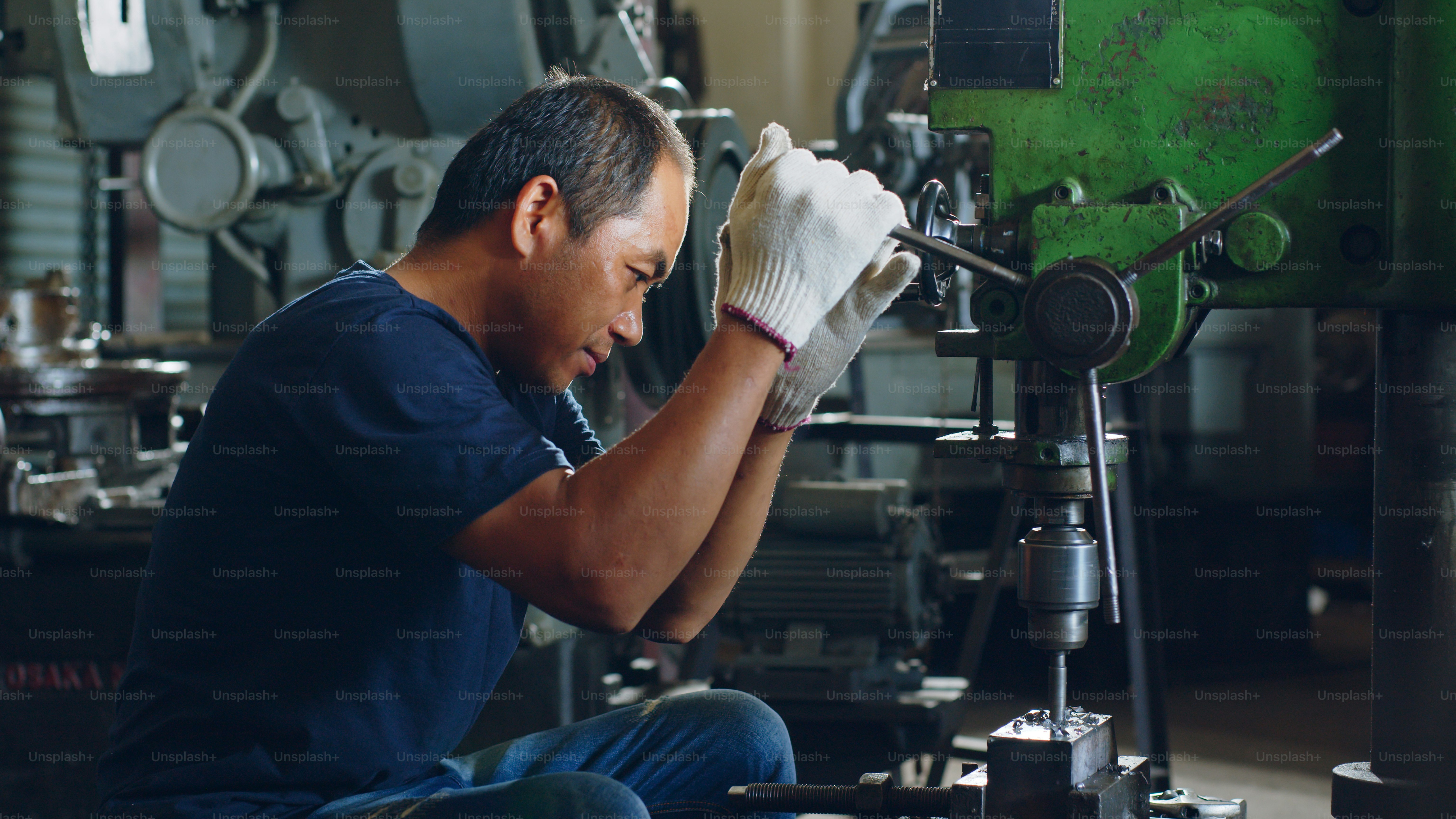 Technician worker using drilling machine for metalworking in workshop ...