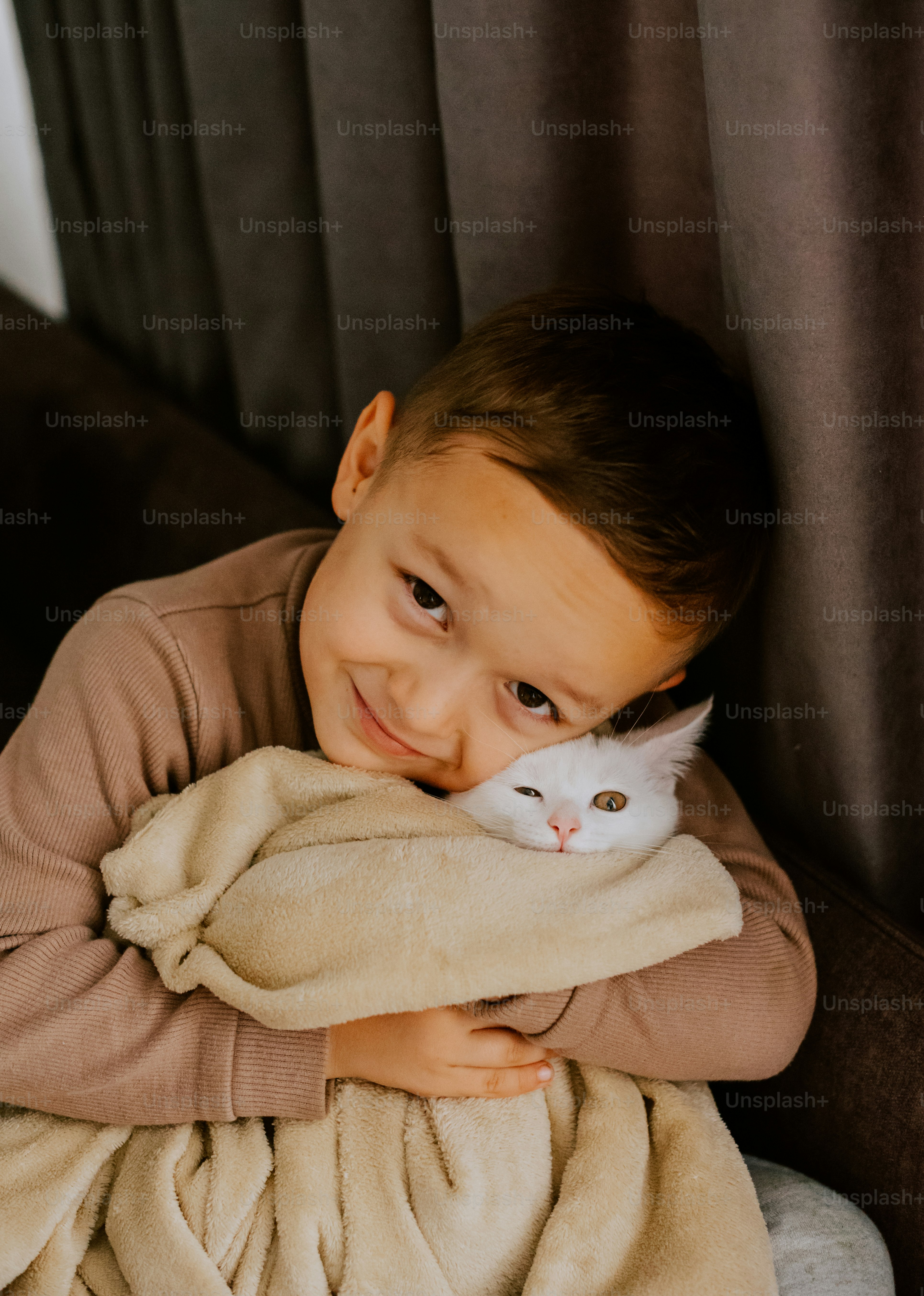 A young boy holding a cat wrapped in a blanket photo – Cute cat Image ...
