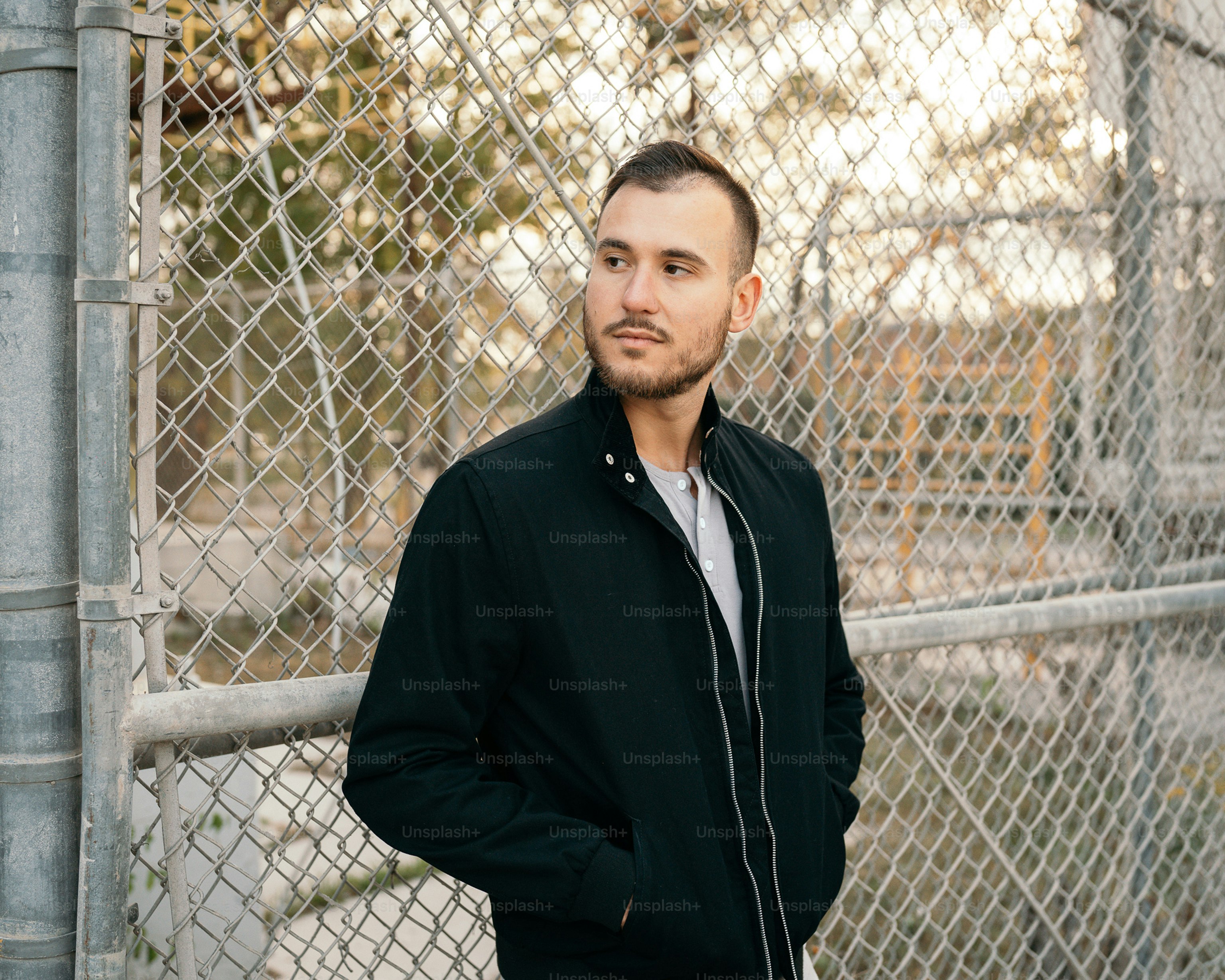 A man standing in front of a chain link fence photo – Jacket man Image ...