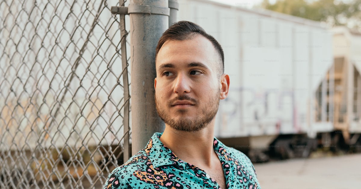A Man Standing Next To A Chain Link Fence Photo Dude Image On Unsplash