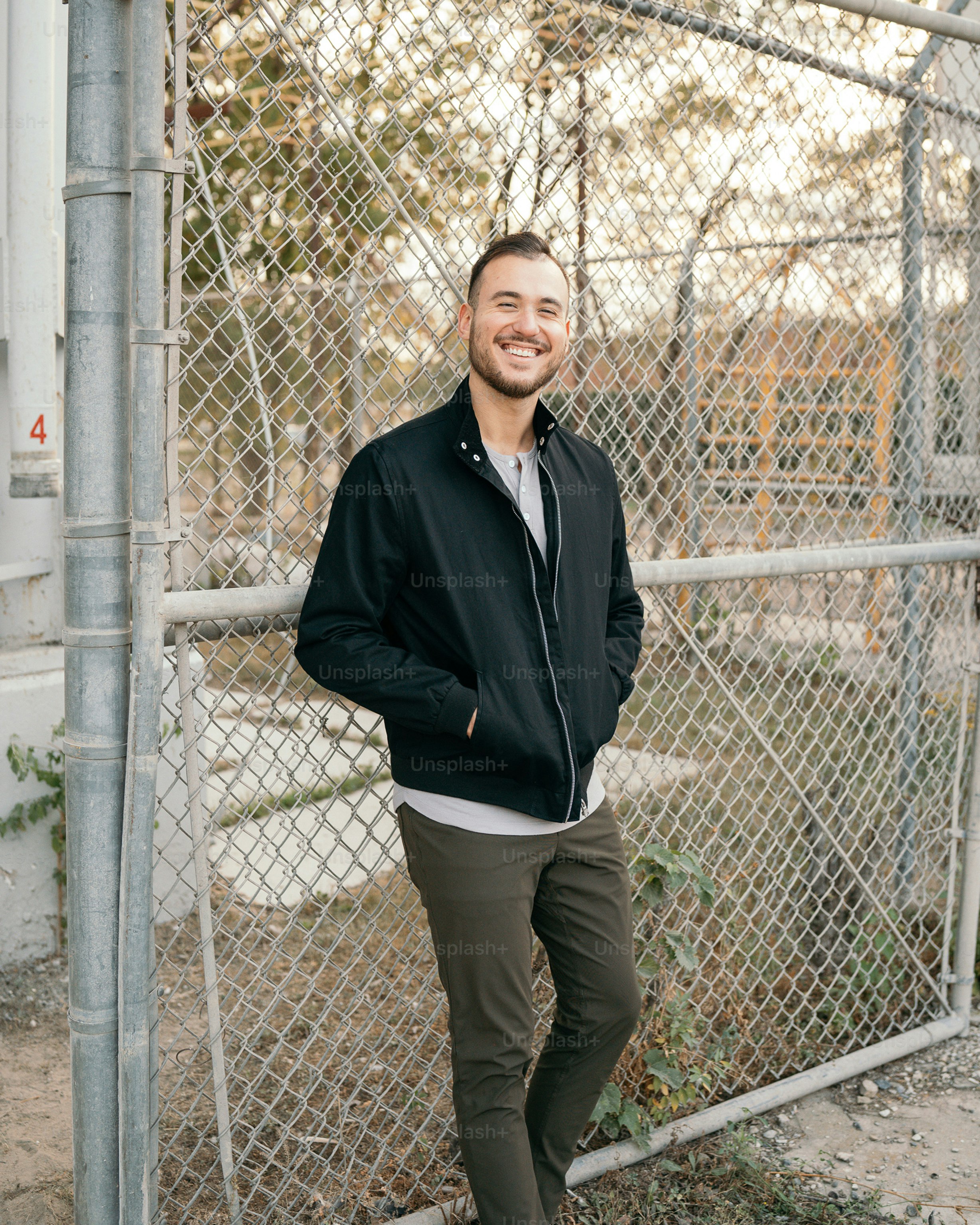A man standing in front of a chain link fence photo – Smiling Image on ...