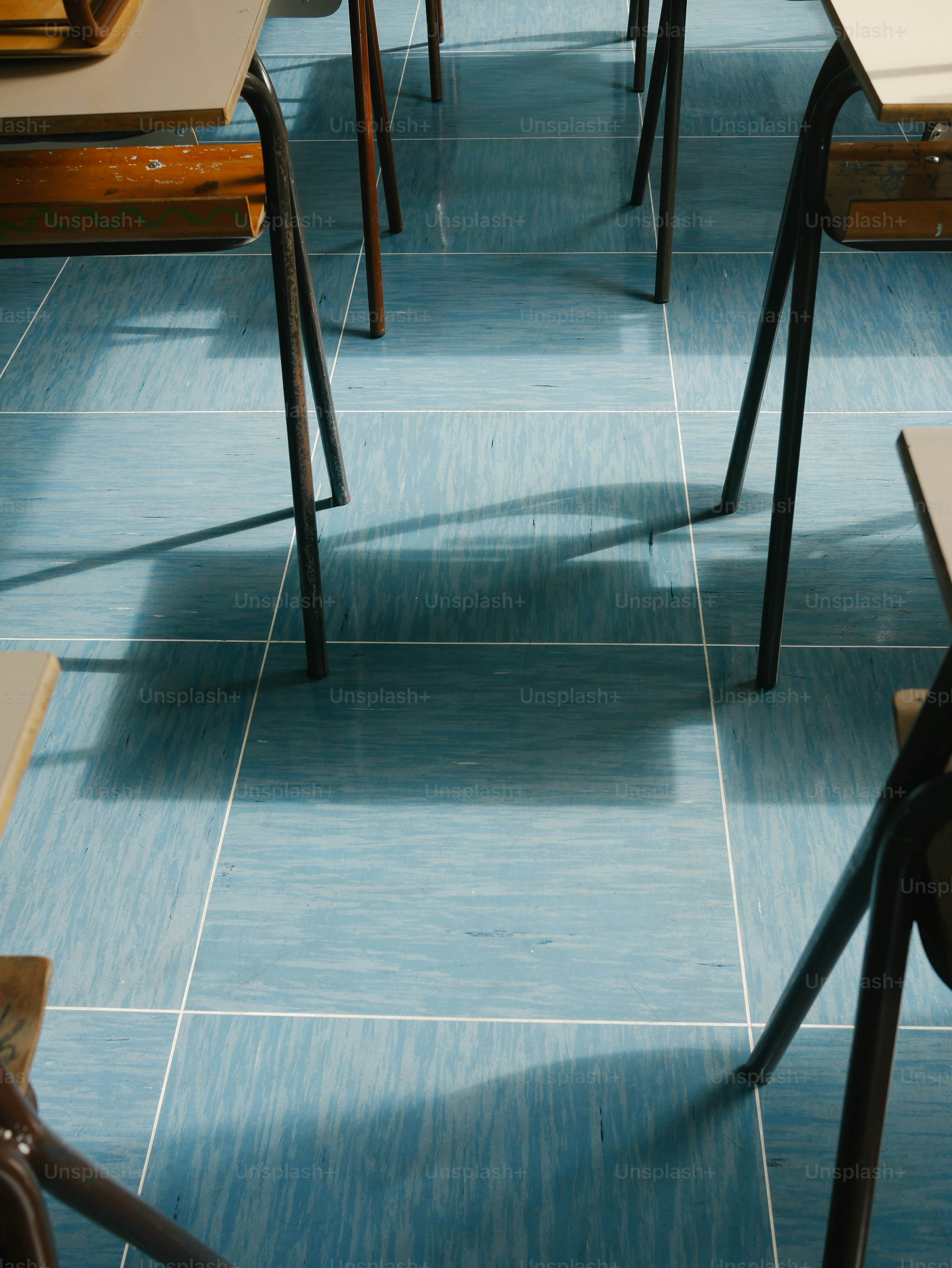 A classroom with blue flooring and wooden desks photo – Floor Image on ...
