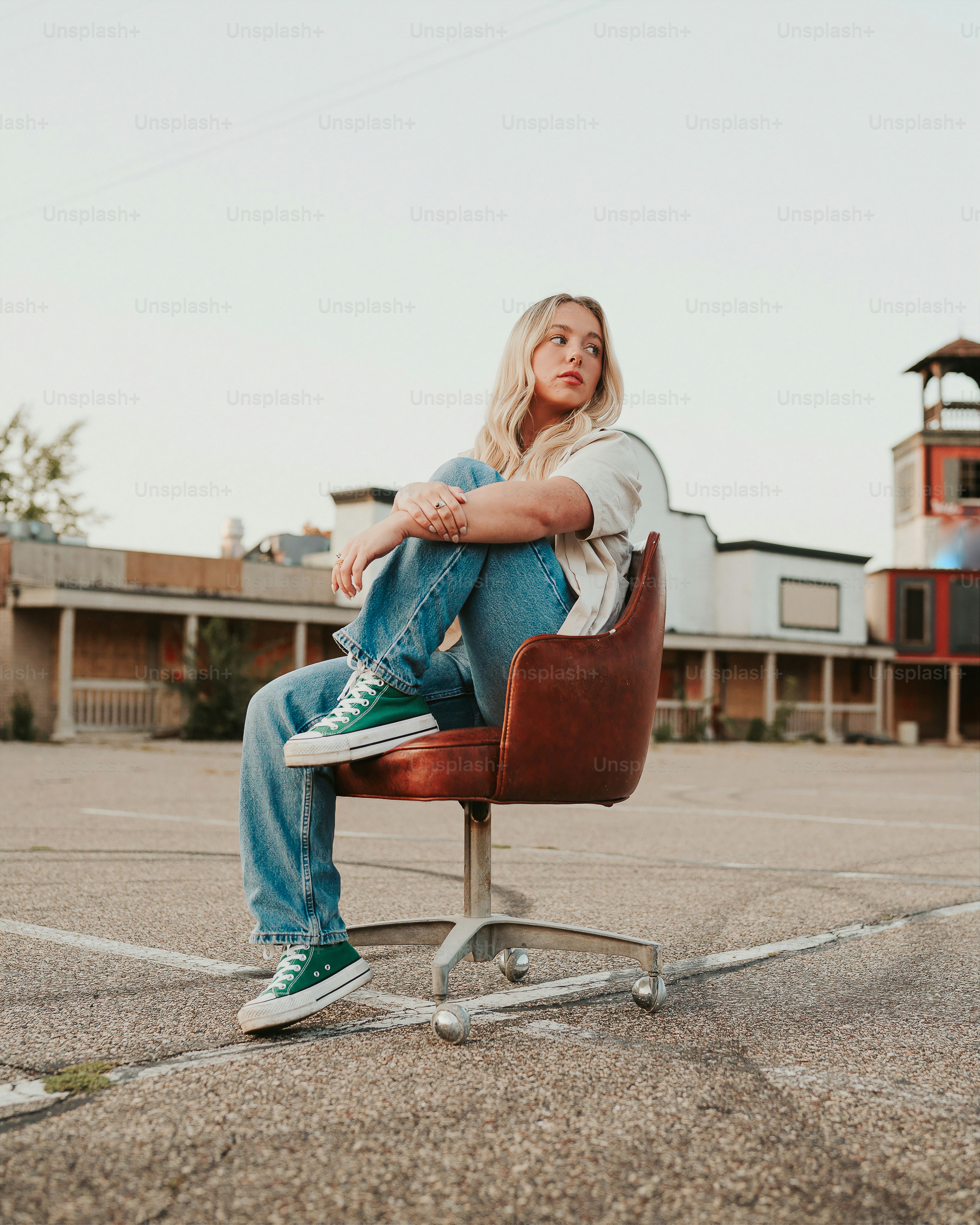 A woman sitting in a chair in a parking lot photo – Sitting in chair ...