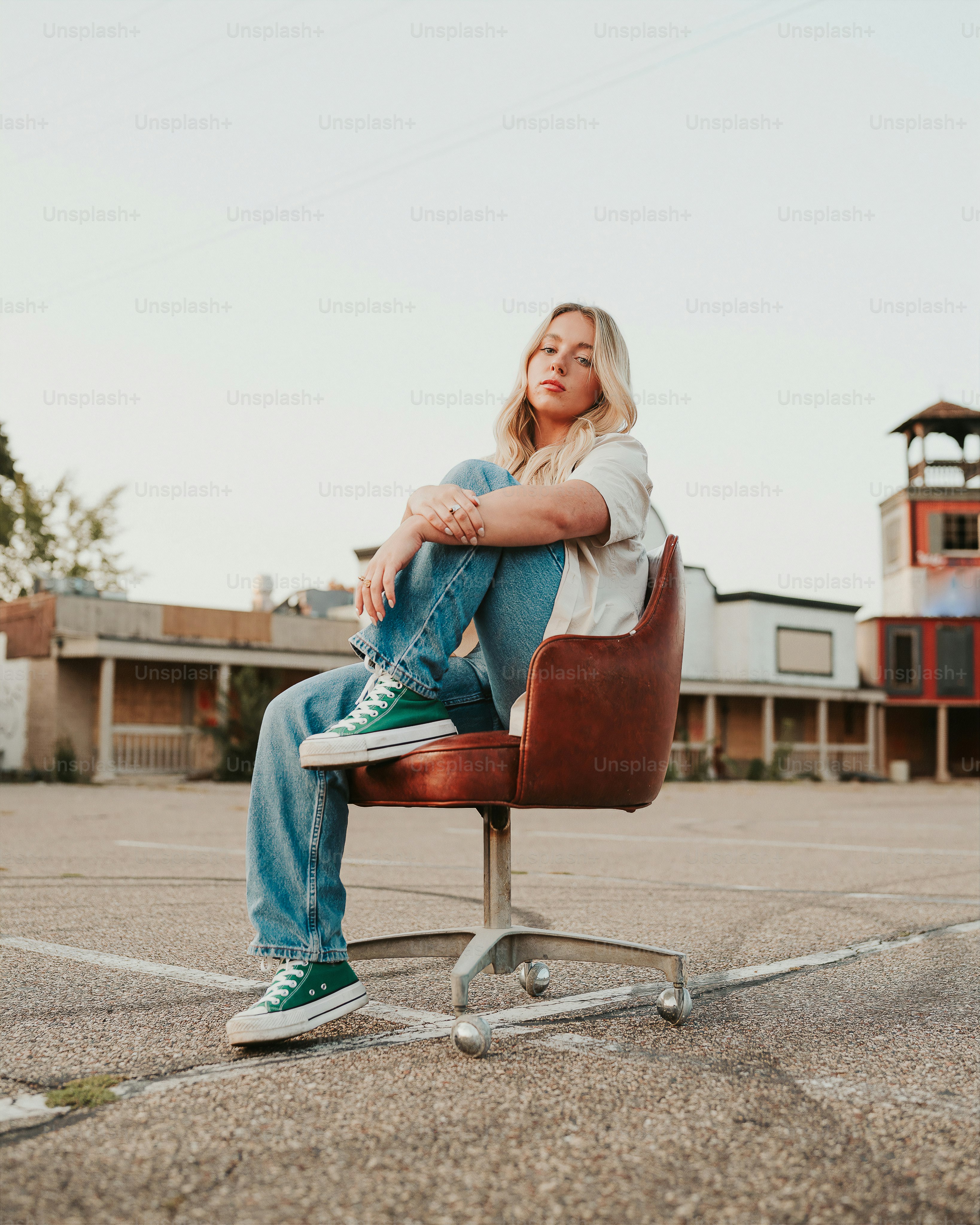 A woman sitting on a chair in a parking lot photo – Sitting Image on ...