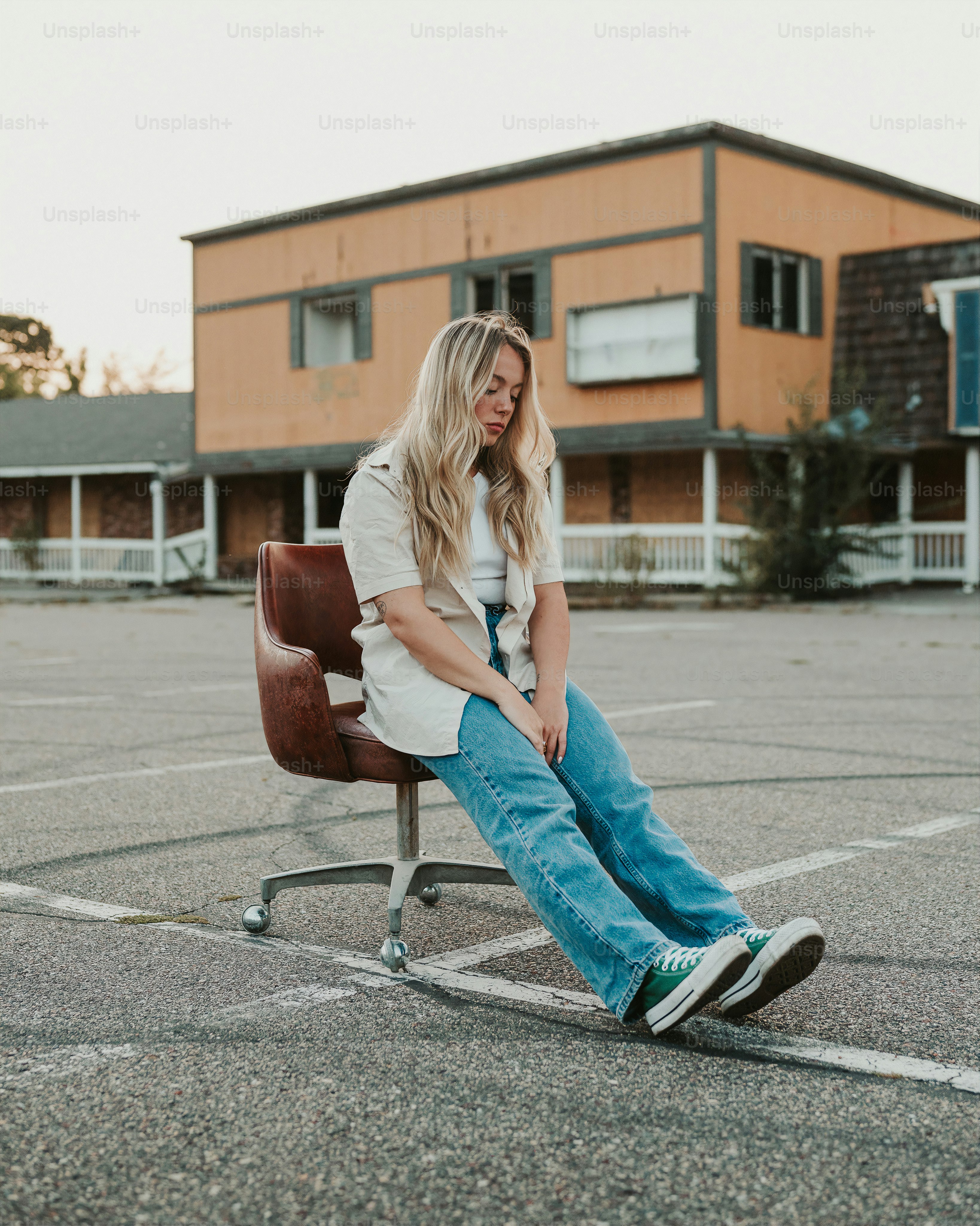 A woman sitting on a chair in a parking lot photo – Sitting Image on ...