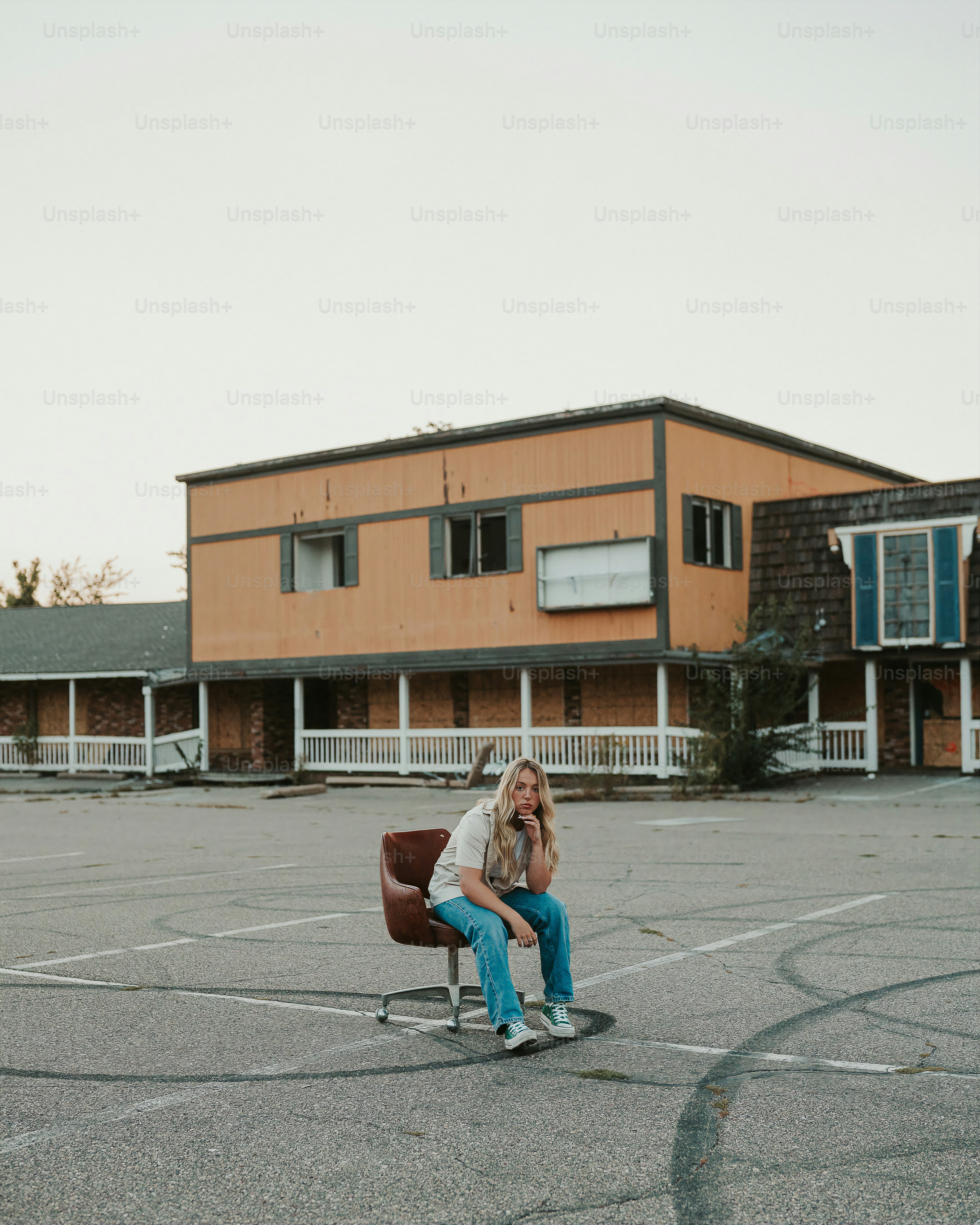 A woman sitting on a chair in a parking lot photo – Sitting Image on ...
