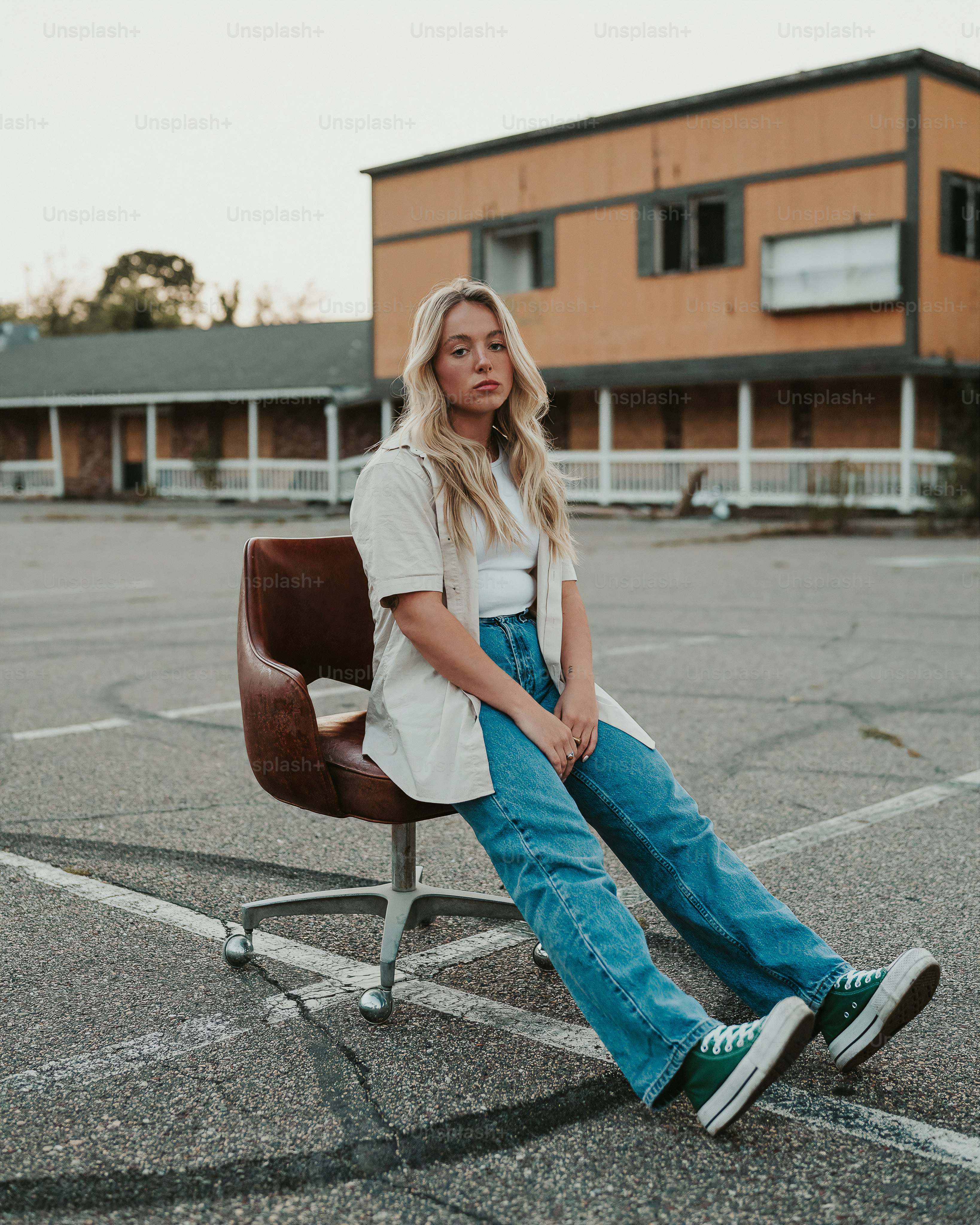 A woman sitting on a chair in a parking lot photo – Sitting Image on ...