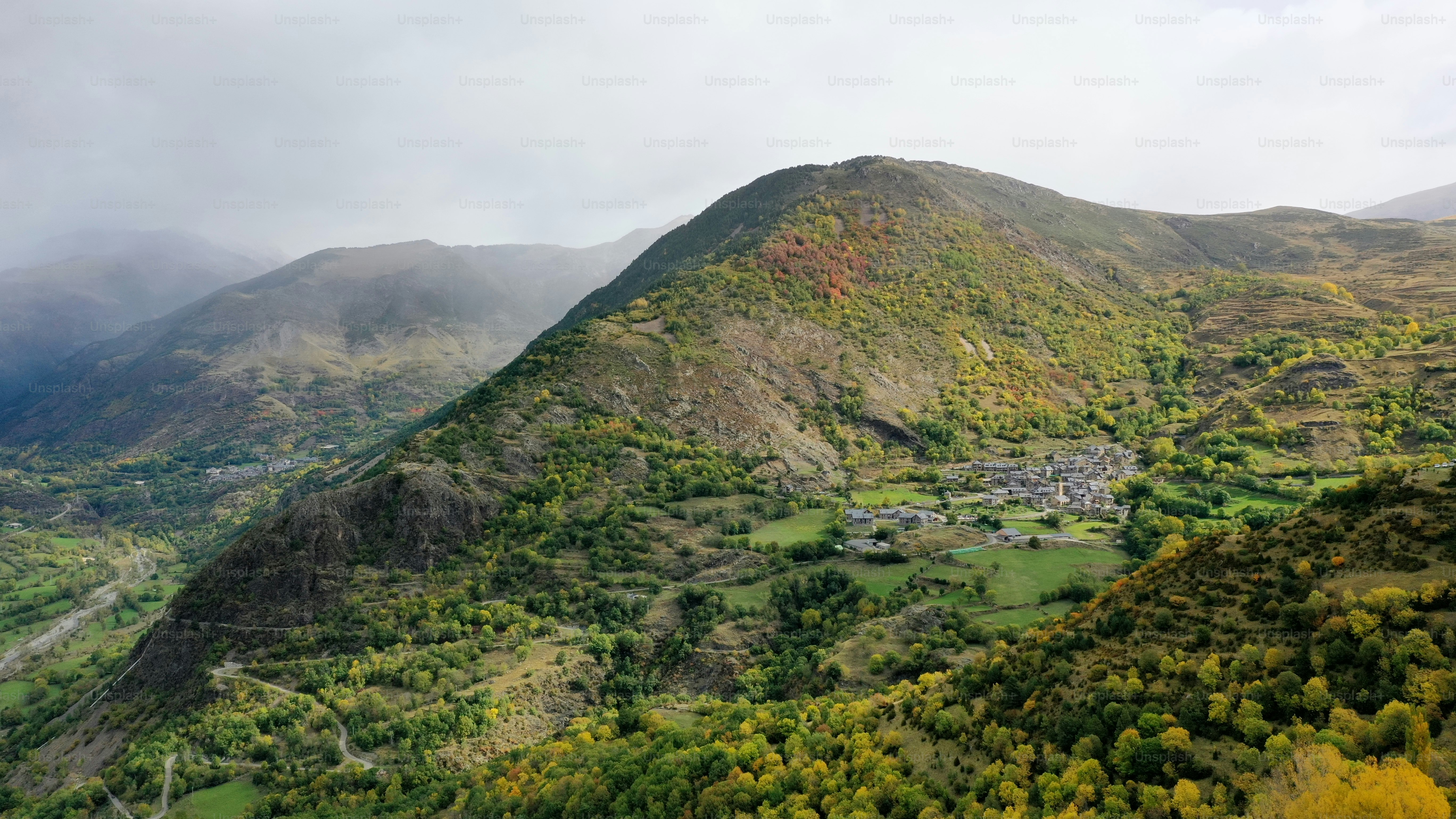 A view of a mountain with a village in the distance photo – Landscape ...