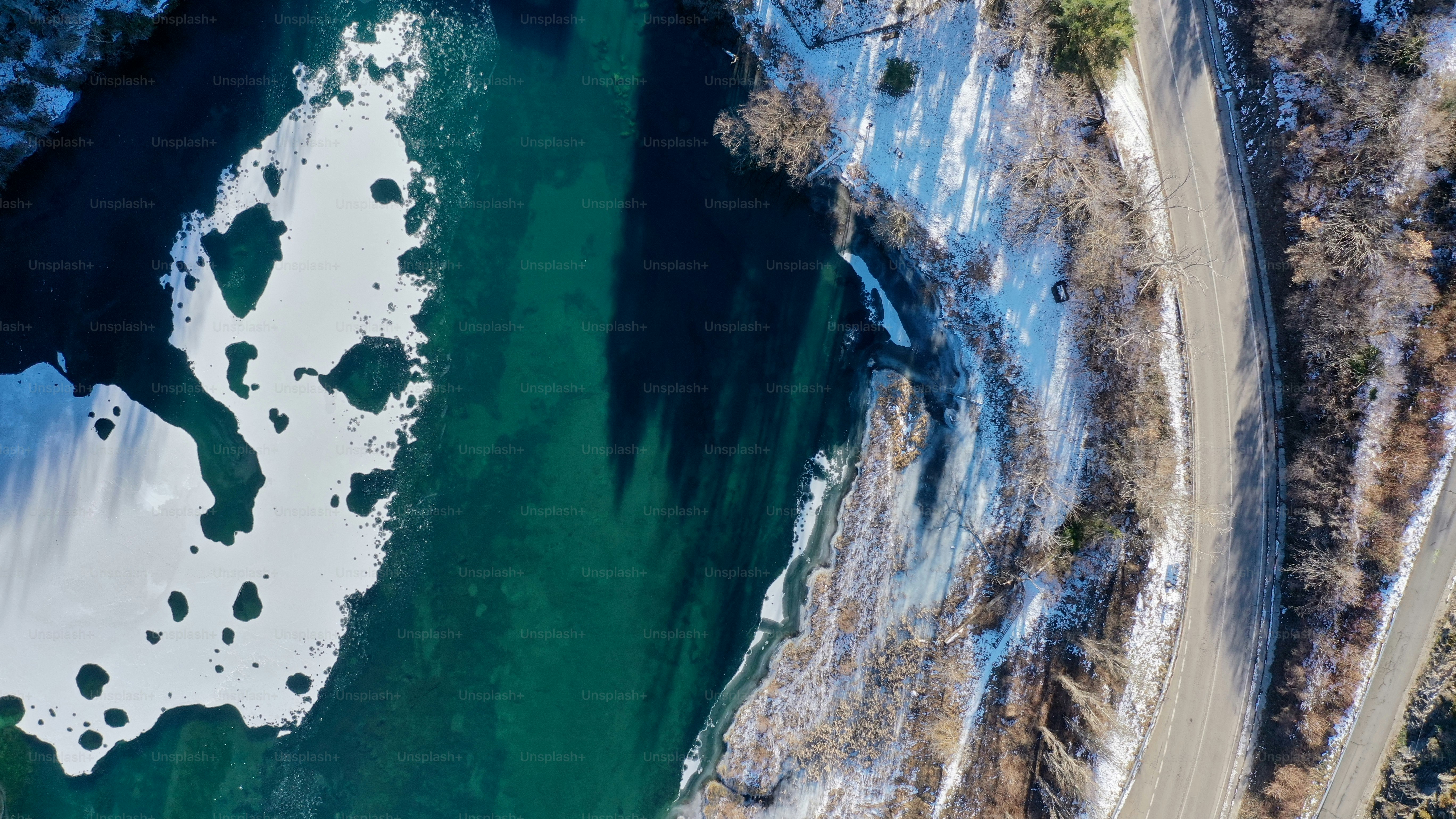 An aerial view of a body of water surrounded by snow photo – Landscape ...