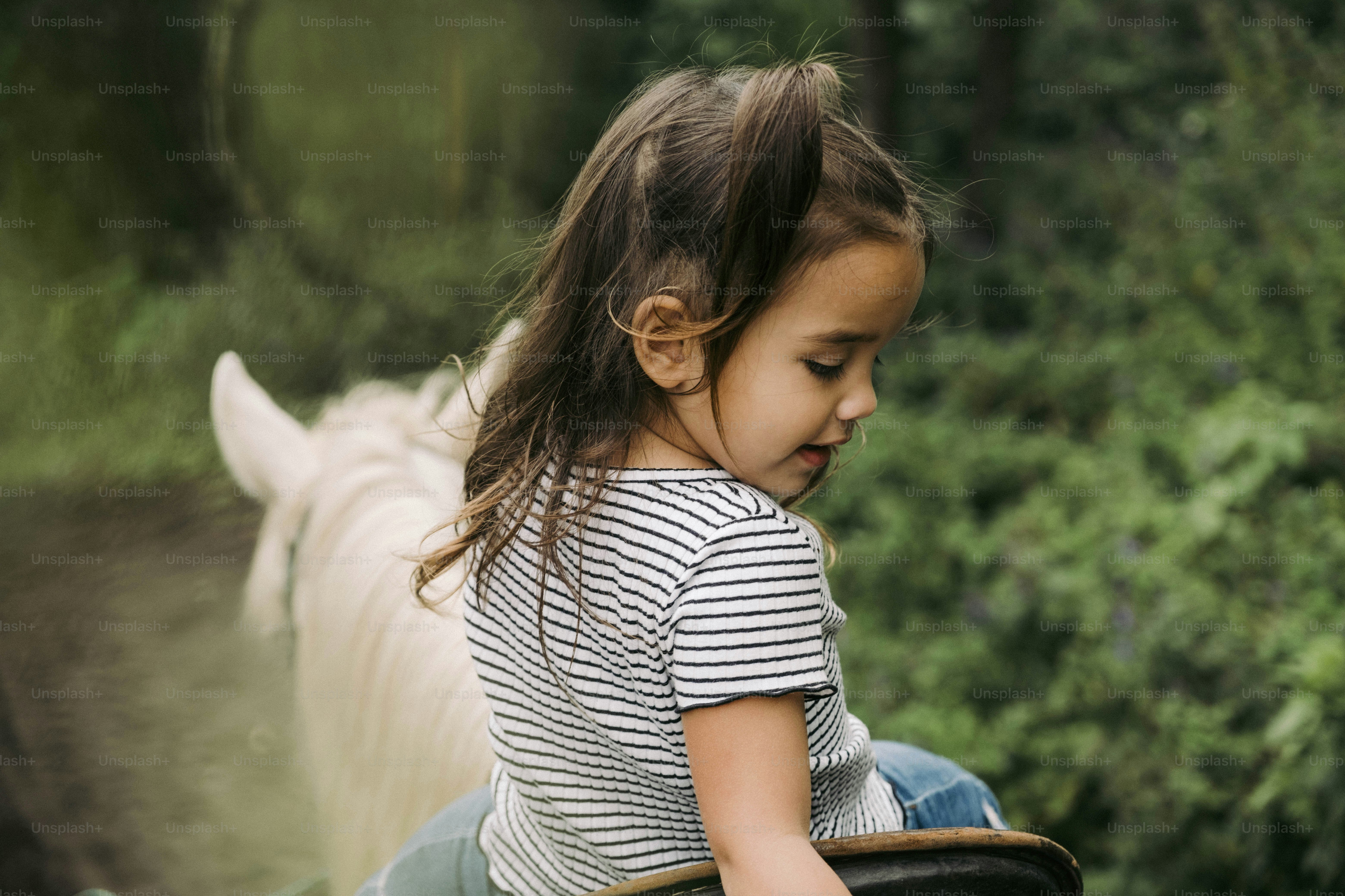 A little girl riding on the back of a white horse photo – Riding horse ...