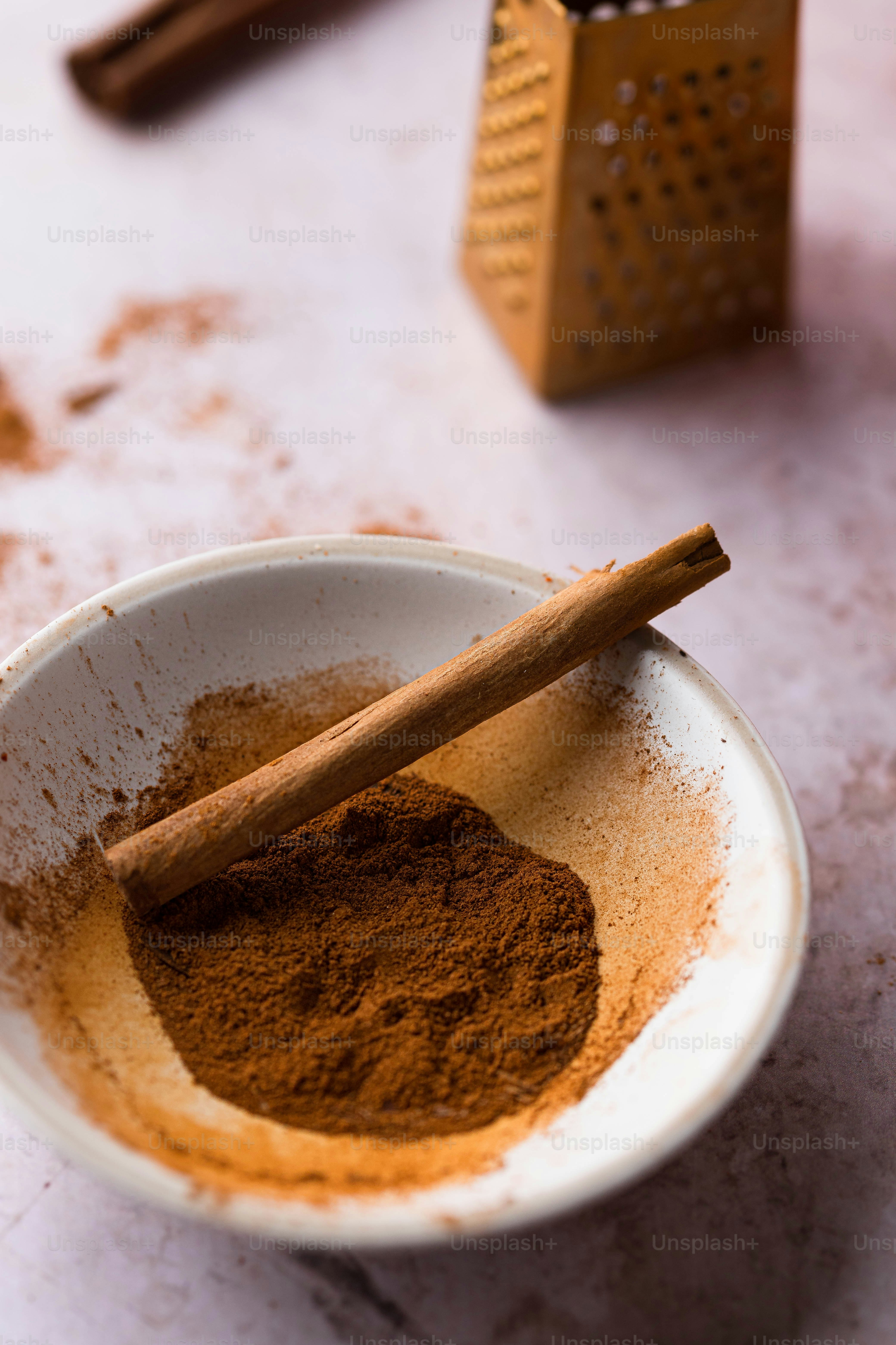 A bowl of cinnamon powder with a cinnamon stick sticking out of it ...