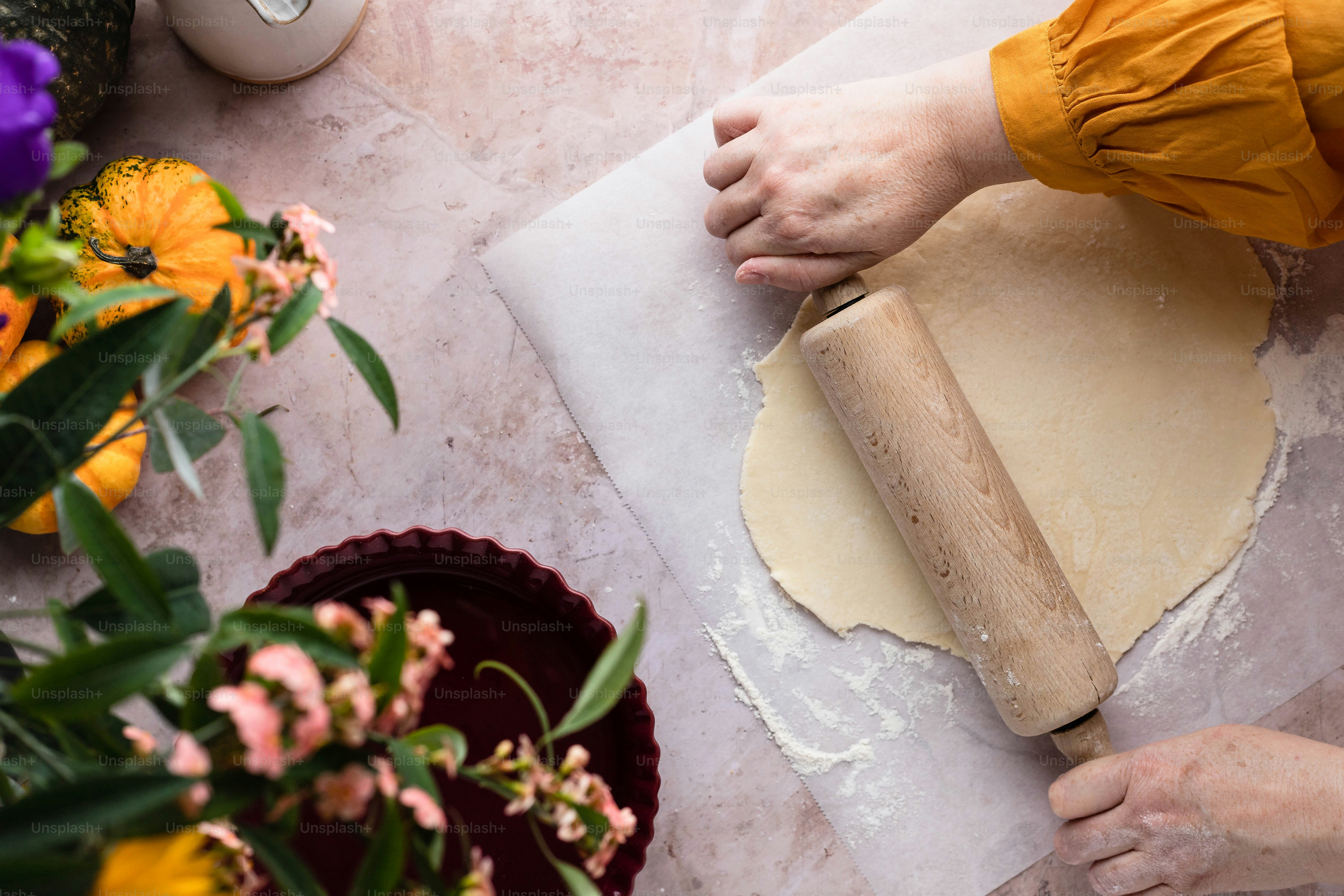 A person rolling dough on a table with flowers photo – Food Image on ...