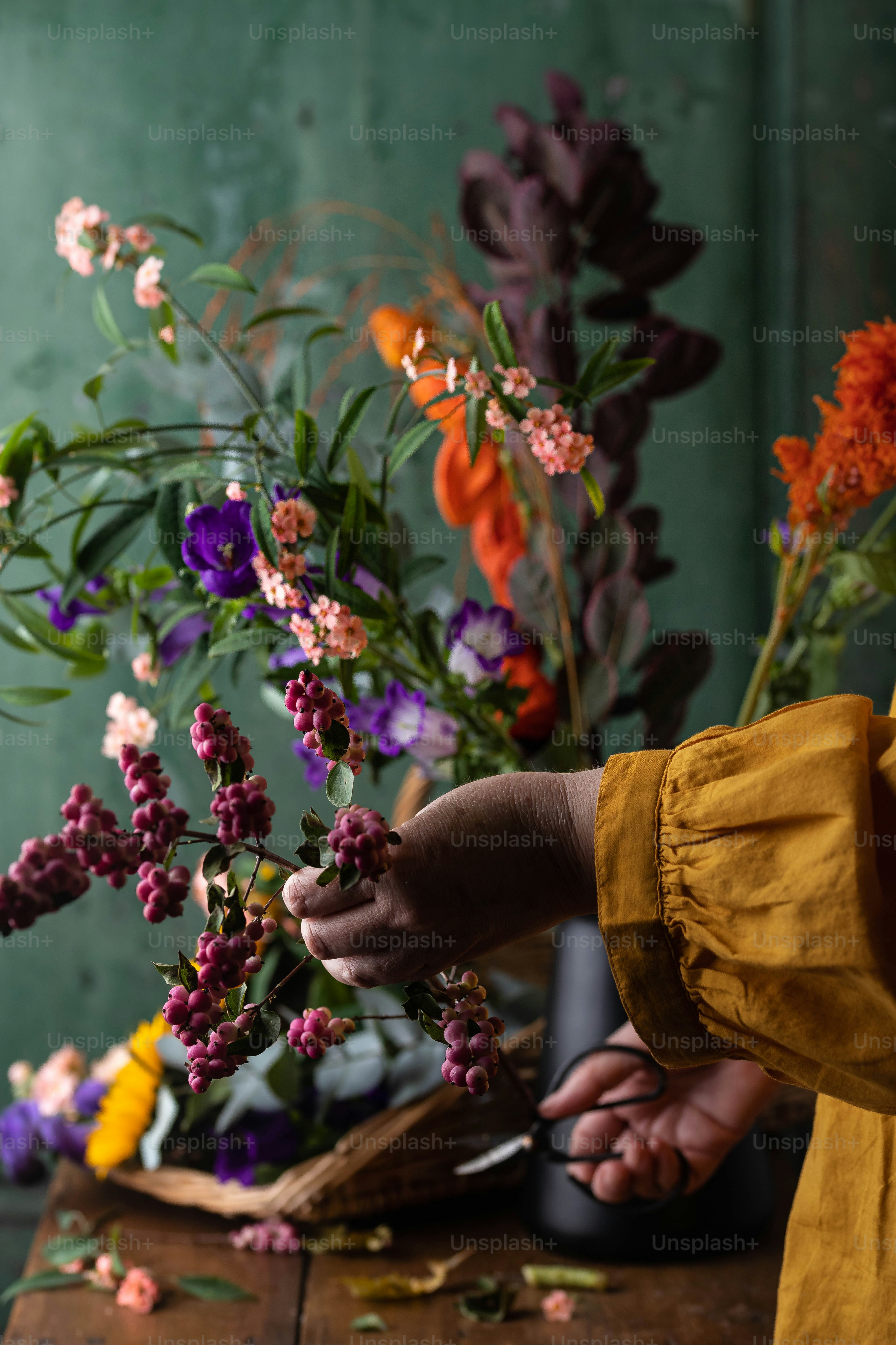 A person arranging flowers in a vase on a table photo – Flower ...
