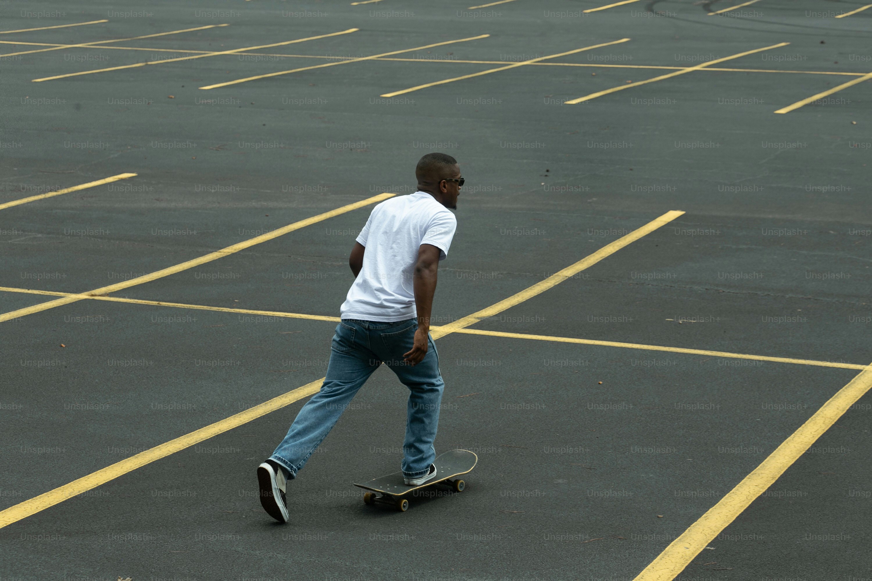 A man riding a skateboard across a parking lot photo – Mens fashion ...