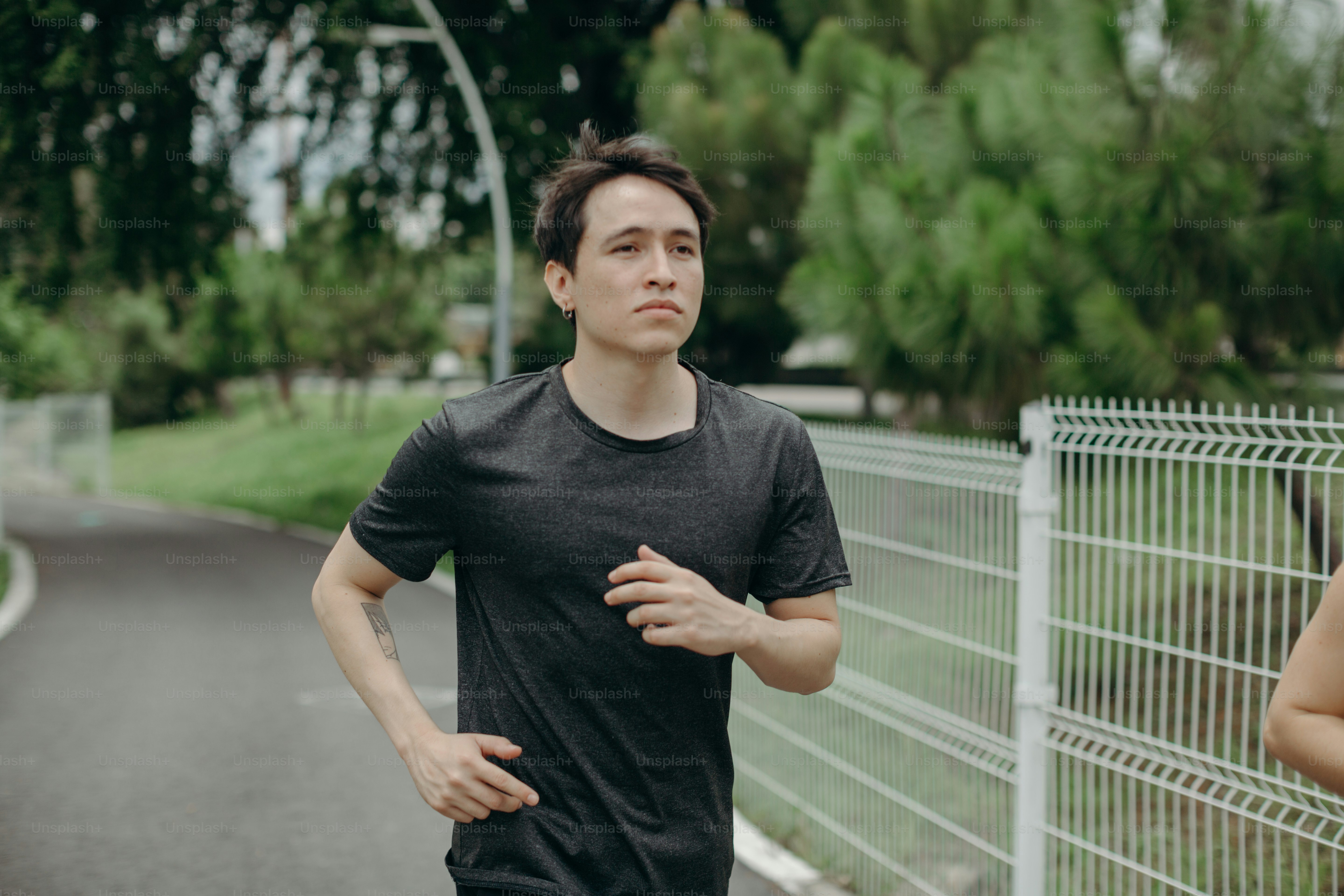 A man running down a street next to a fence photo – Fitness Image on ...