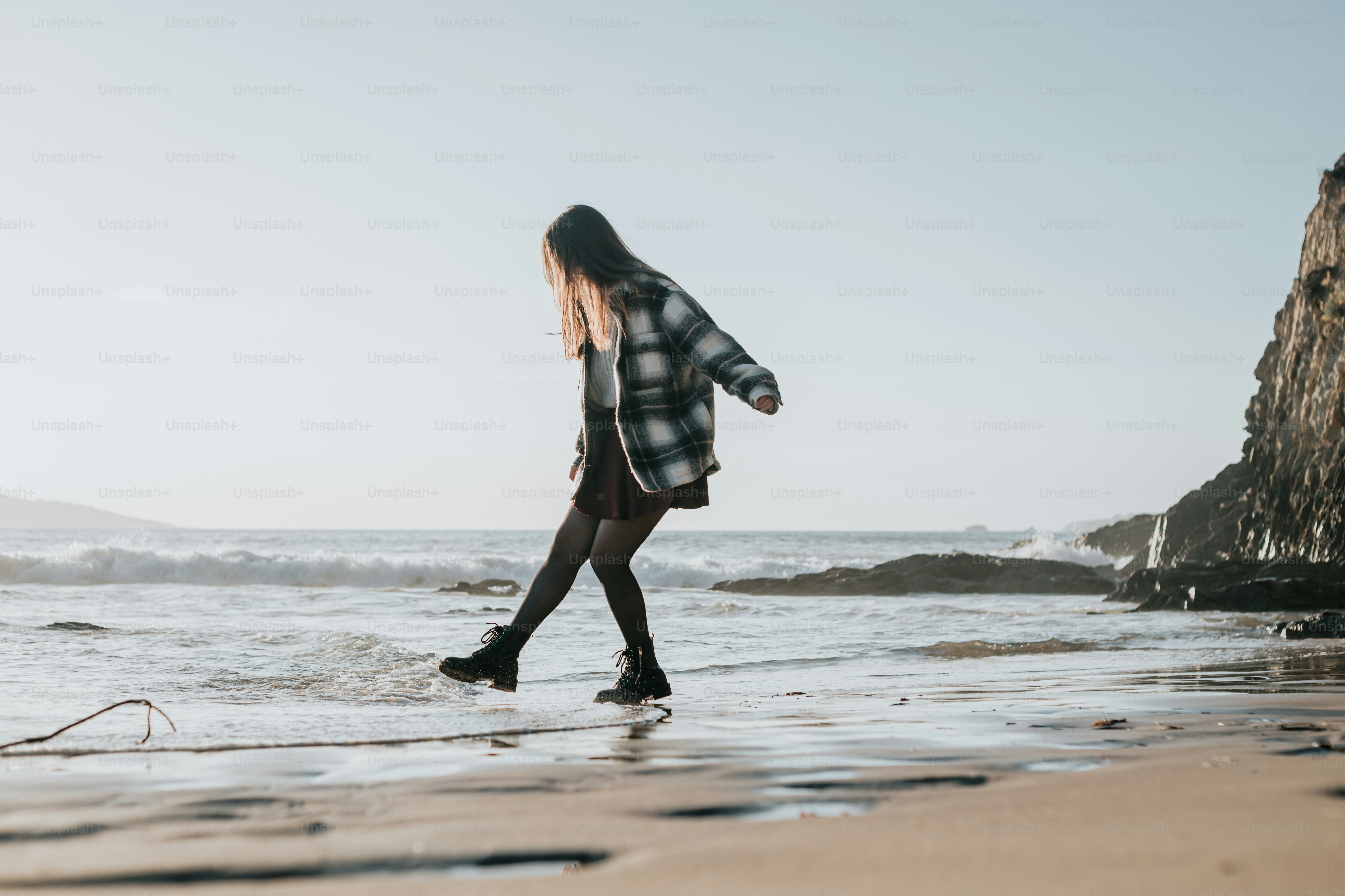 A woman walking along a beach next to the ocean photo – Female Image on ...