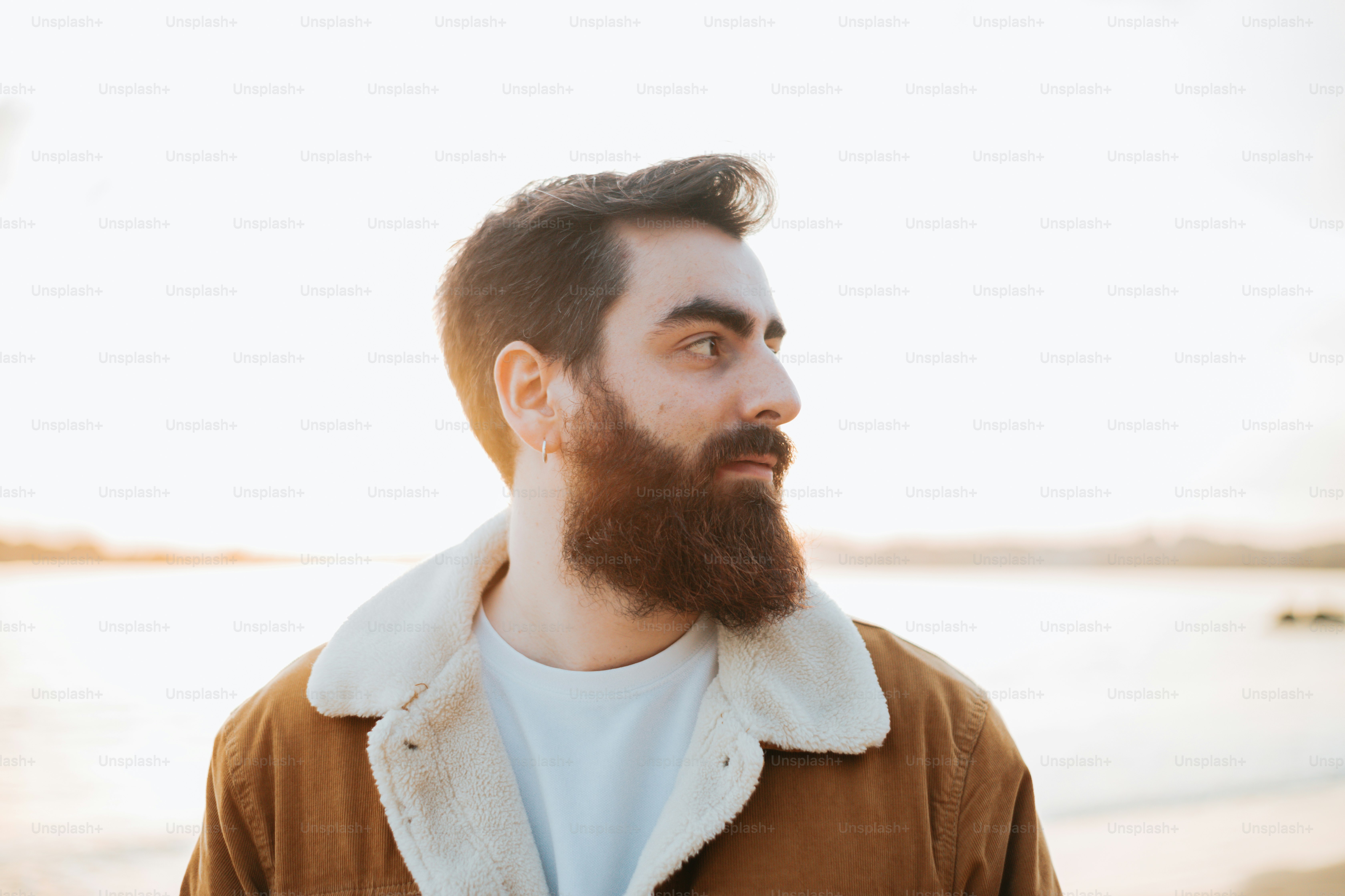 A man with a goatee and a beard standing on a beach photo – Hairy man ...